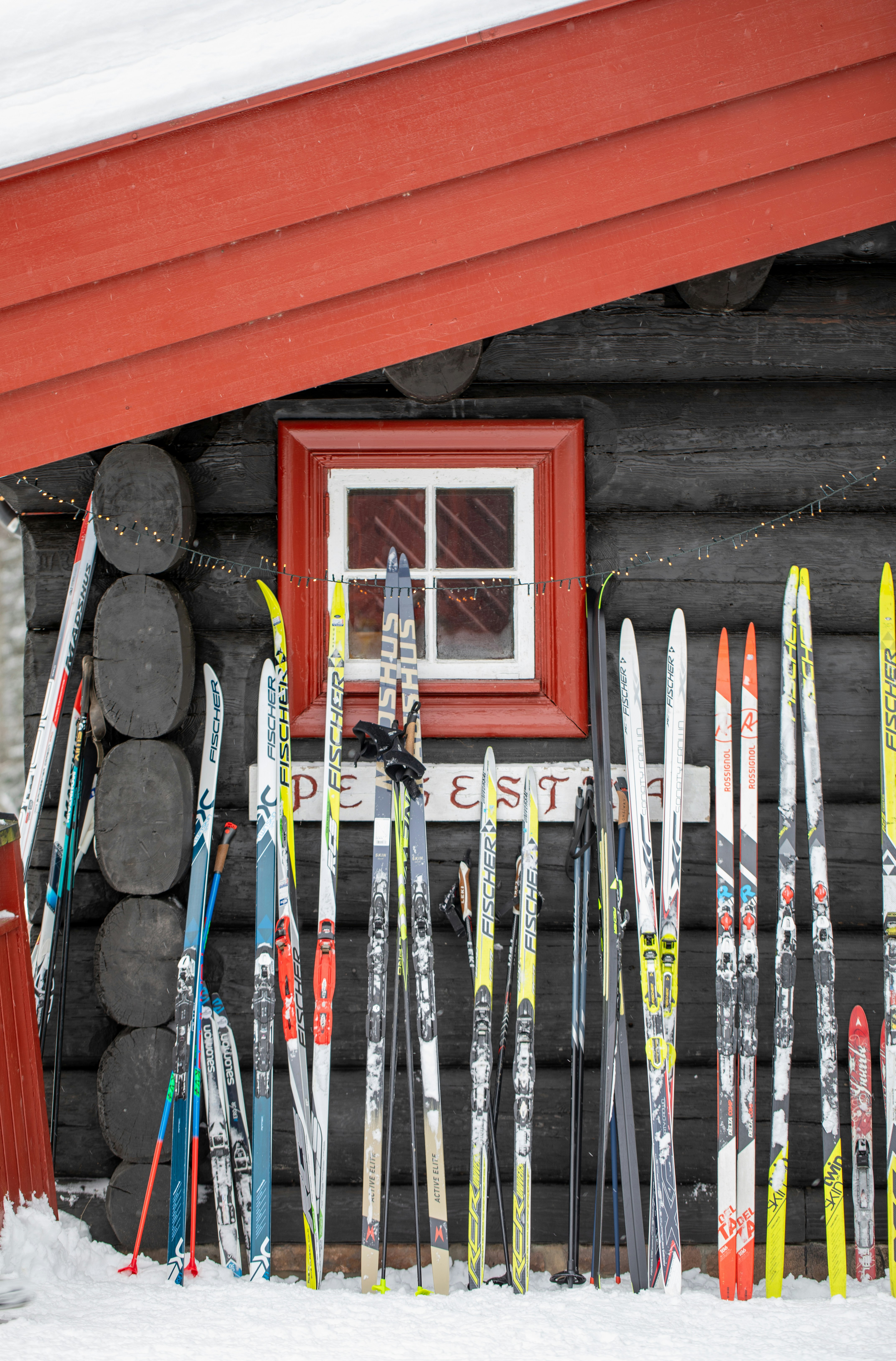 Ski Racks Against Log Cabin: A Row of Polished Poles and a Red Window