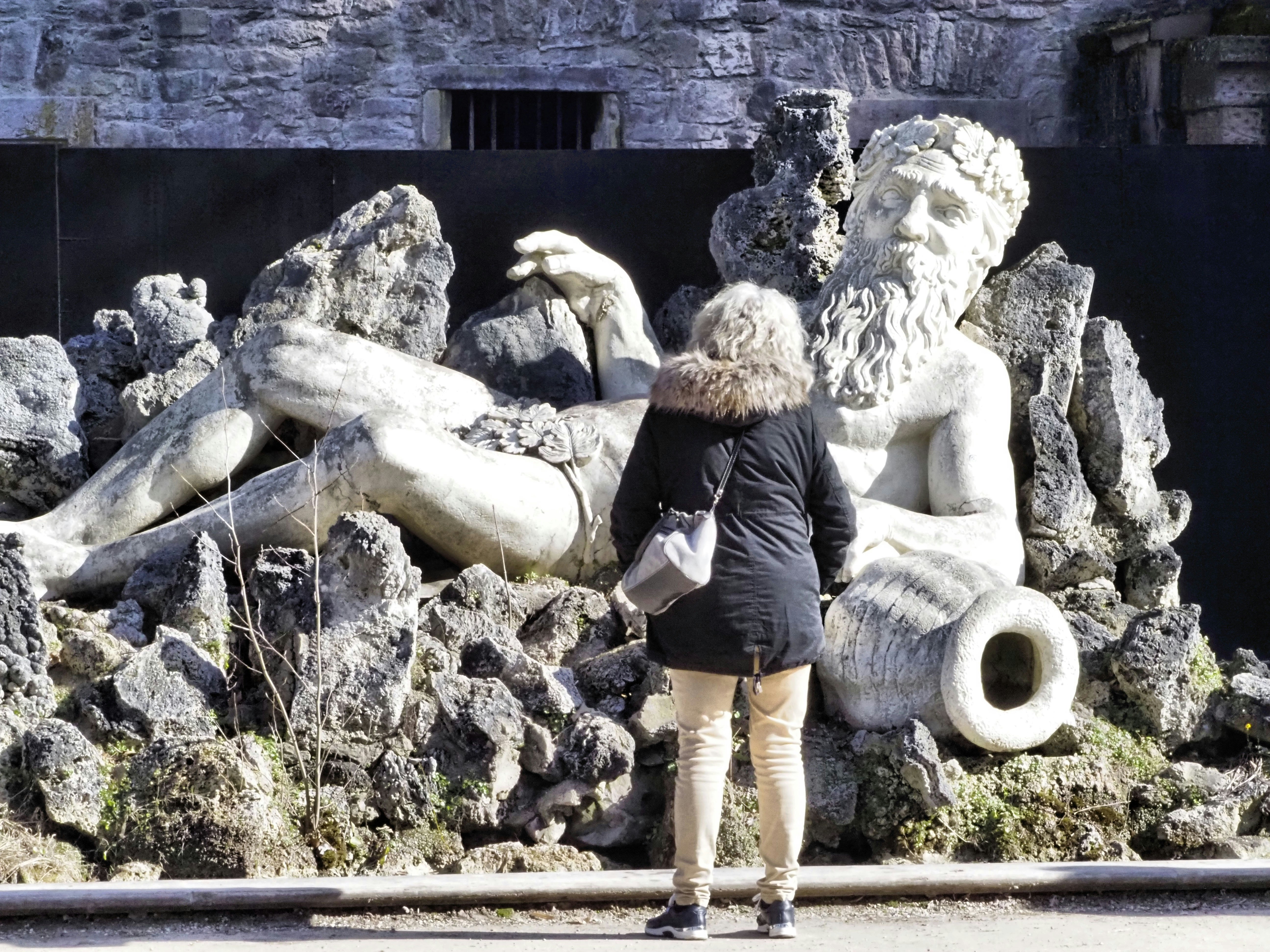 Visitor in front of a weathered classical sculpture pool