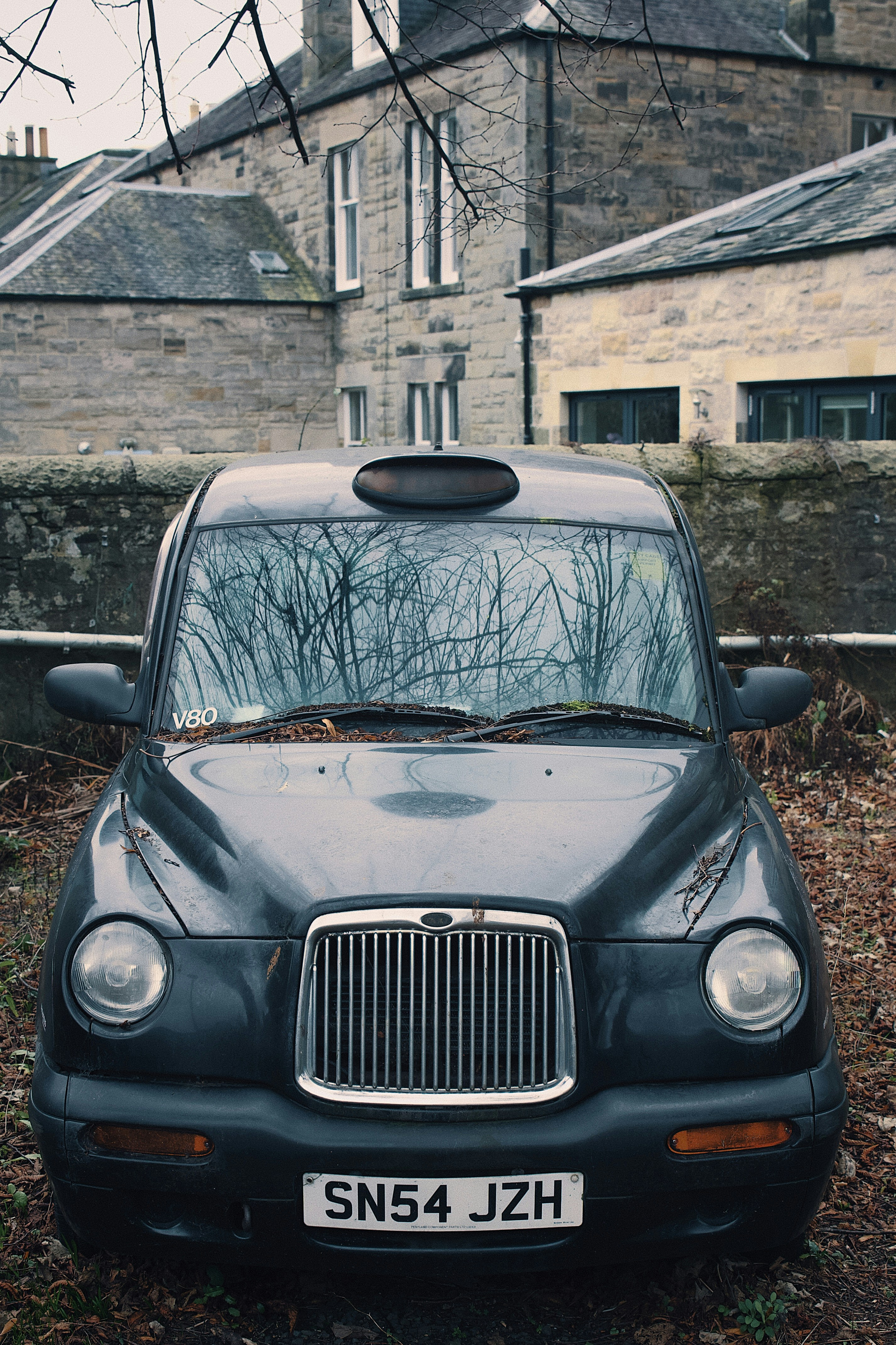 Front-View of a Weathered London Cab Resting Before an Old Stone Courtyard