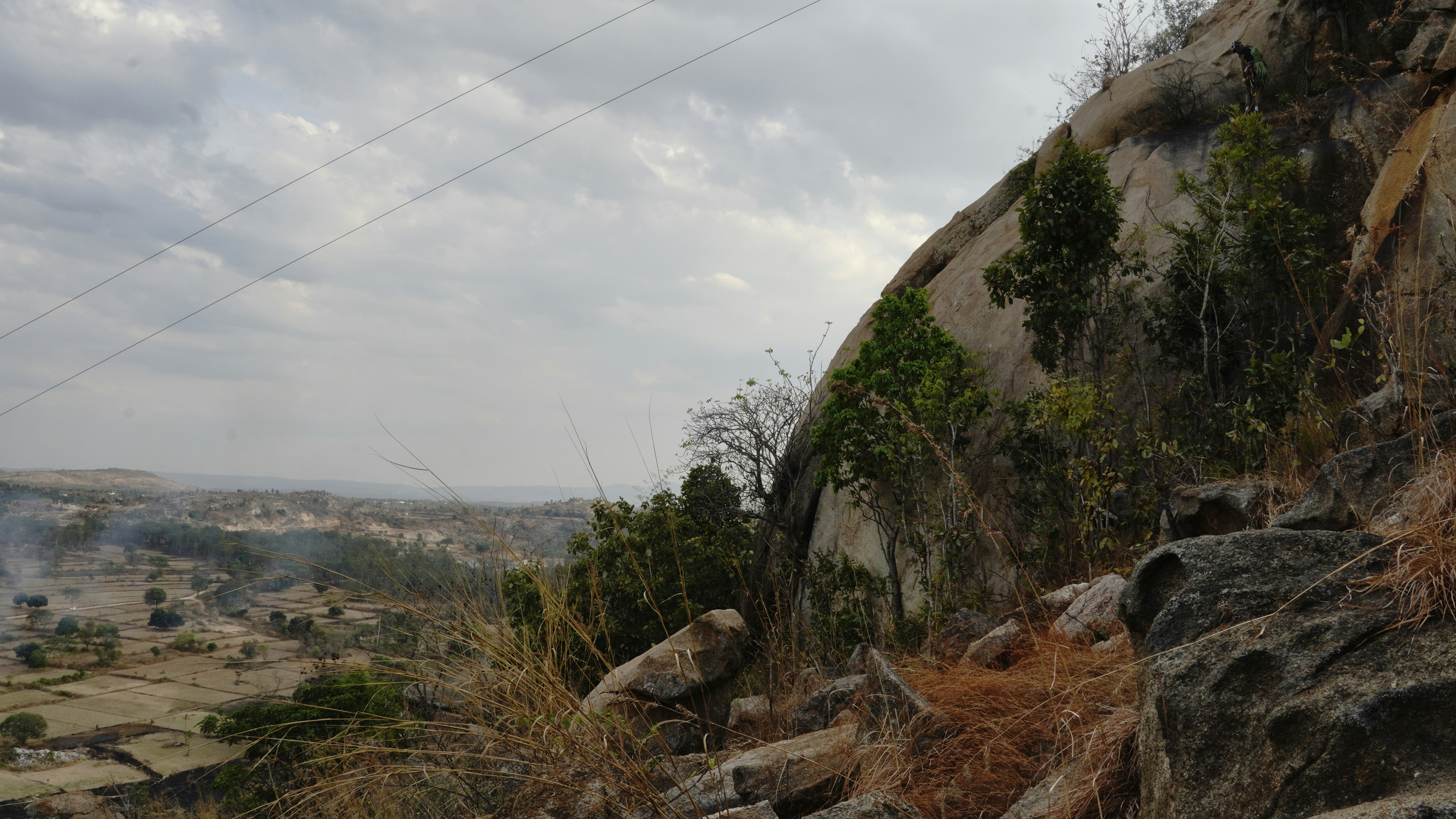 Rugged hillside overlook: sunlit boulders and sparse trees watch over a distant valley