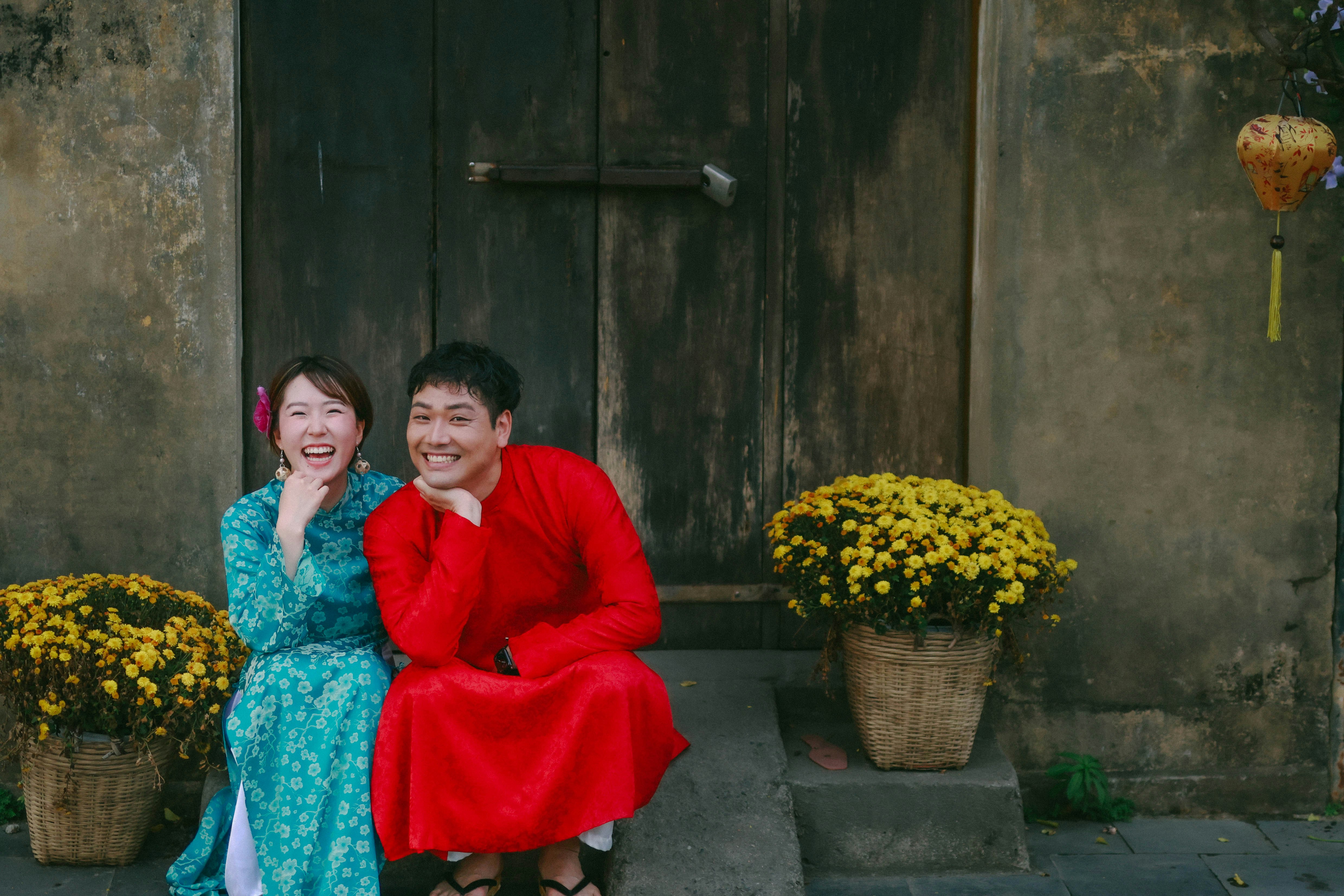 Red-clad companion and teal-dressed friend share a candid moment on a rustic doorstep