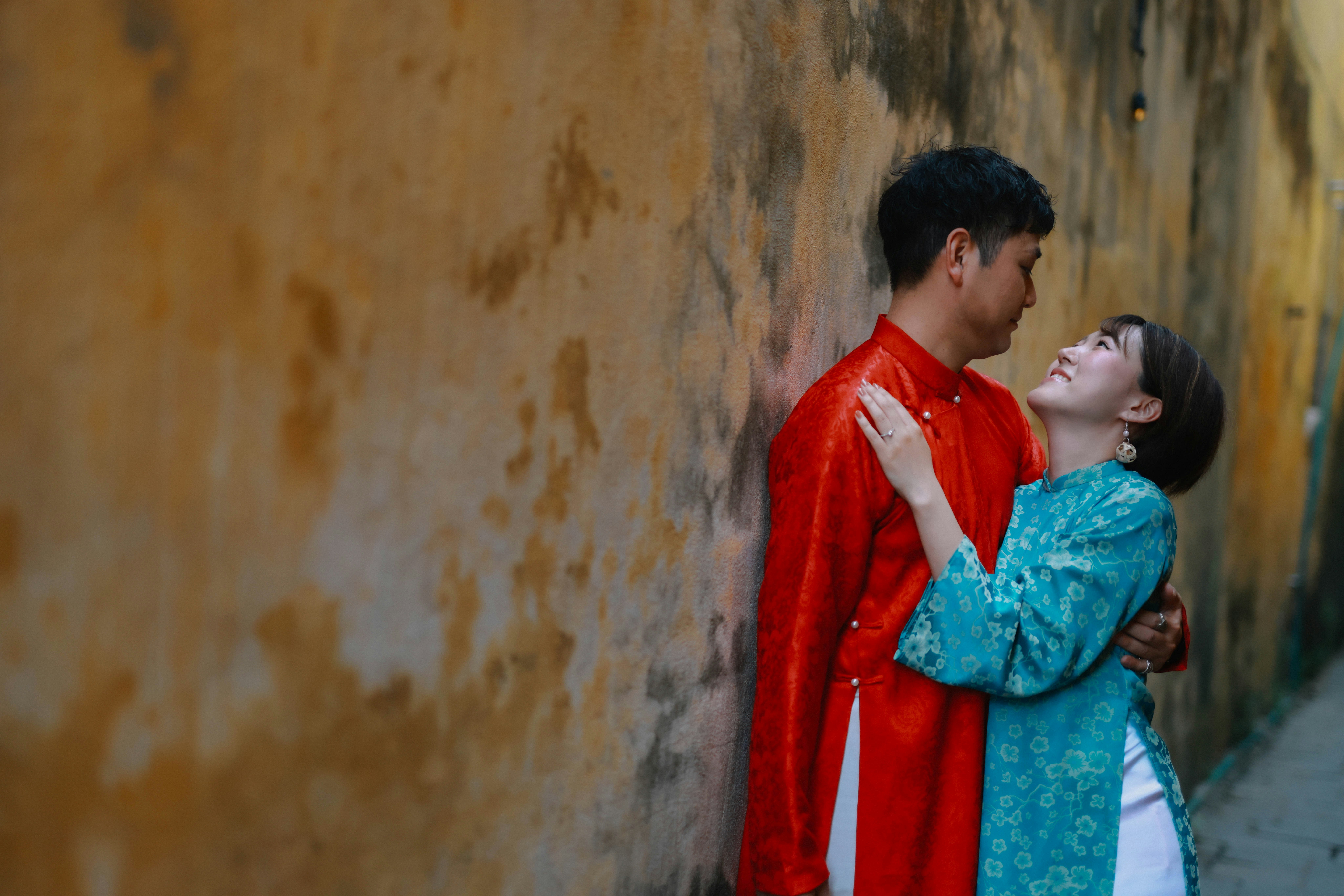 Red Wang and Blue Kim: Embrace Against a Weathered Wall