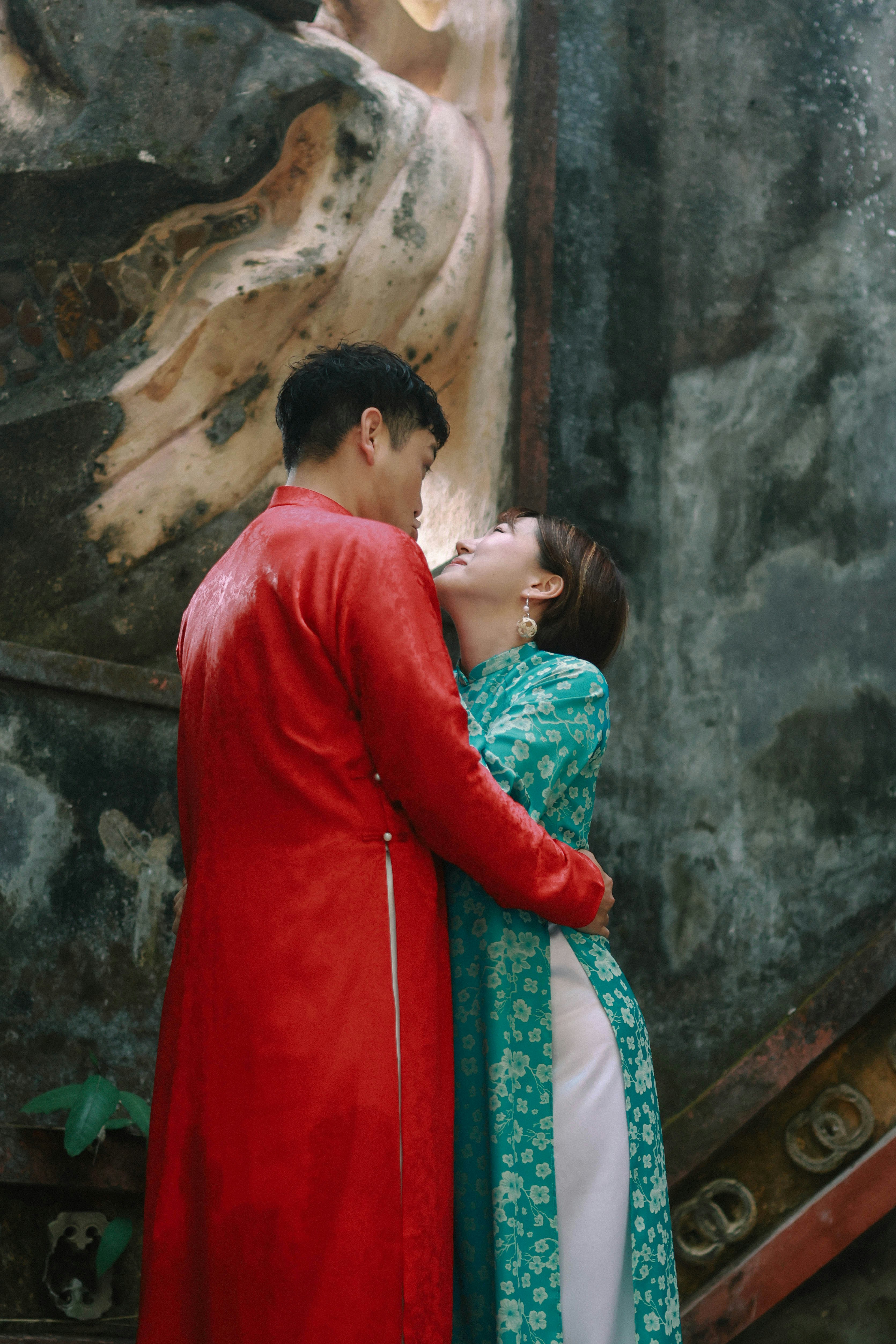 Close embrace beneath a weathered arch: red and teal in a candid moment