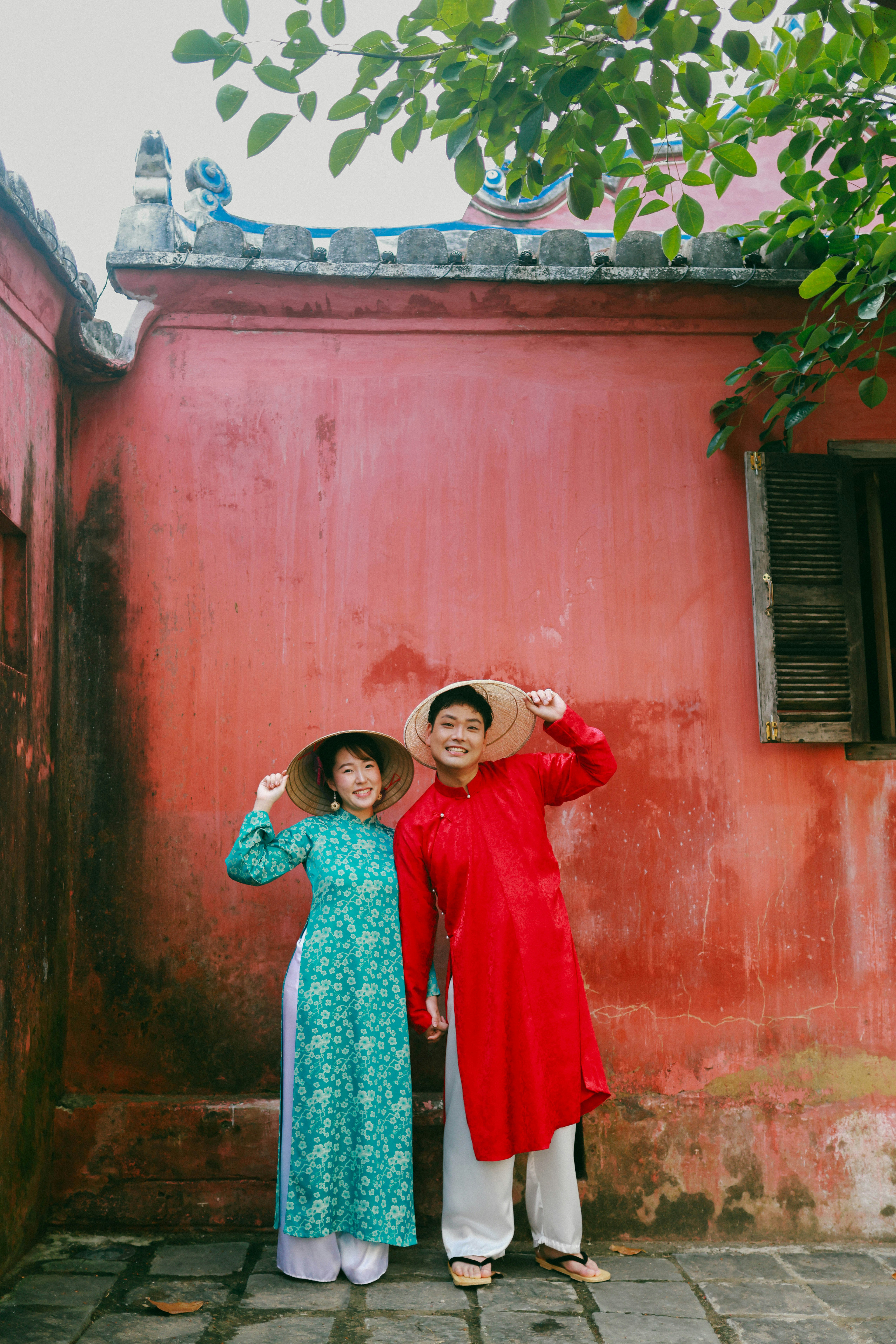 Two Travelers in Front of a Sunlit Red Wall