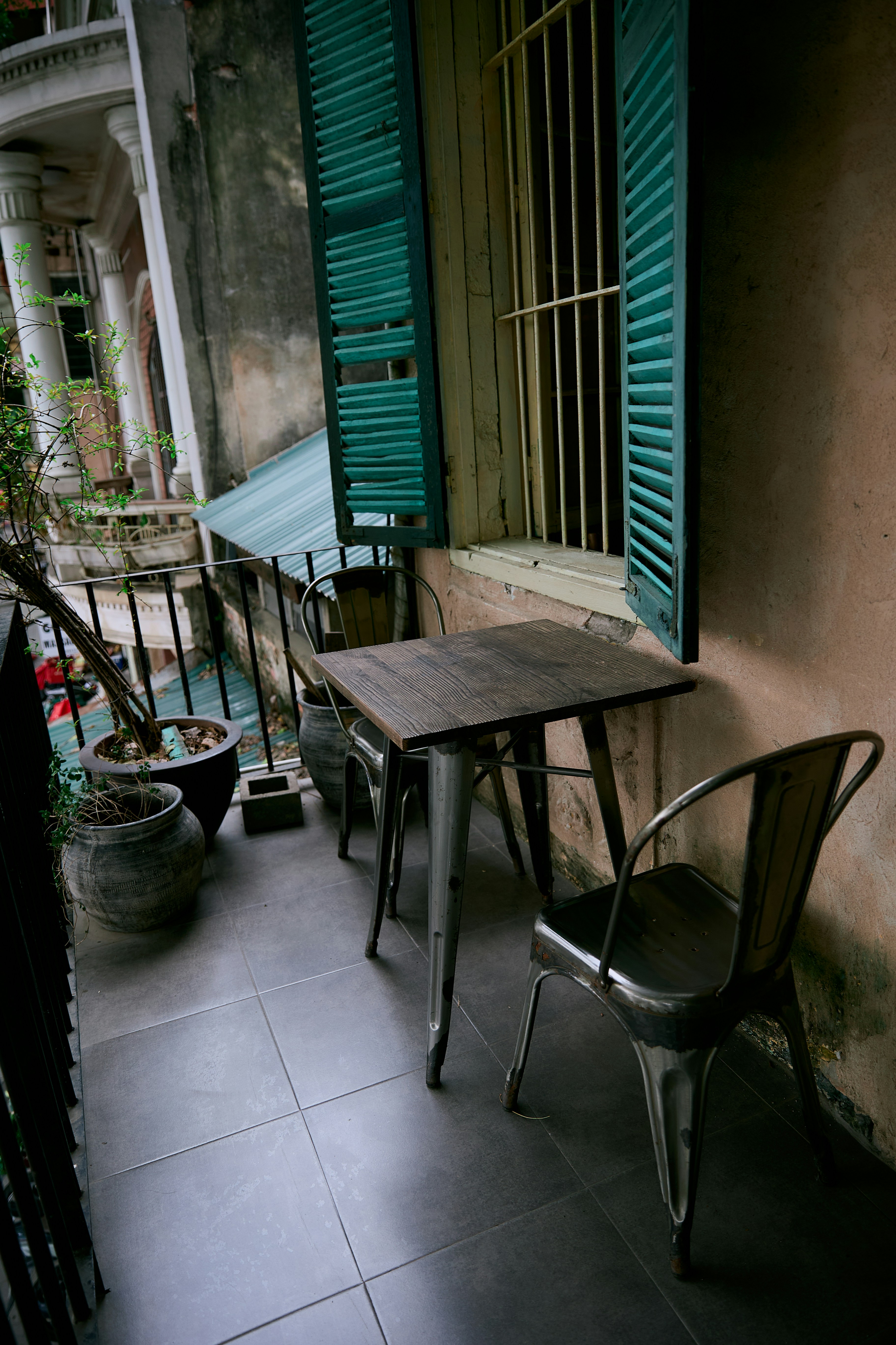 Quiet Balcony Café: A Worn Table and Turquoise Shutters