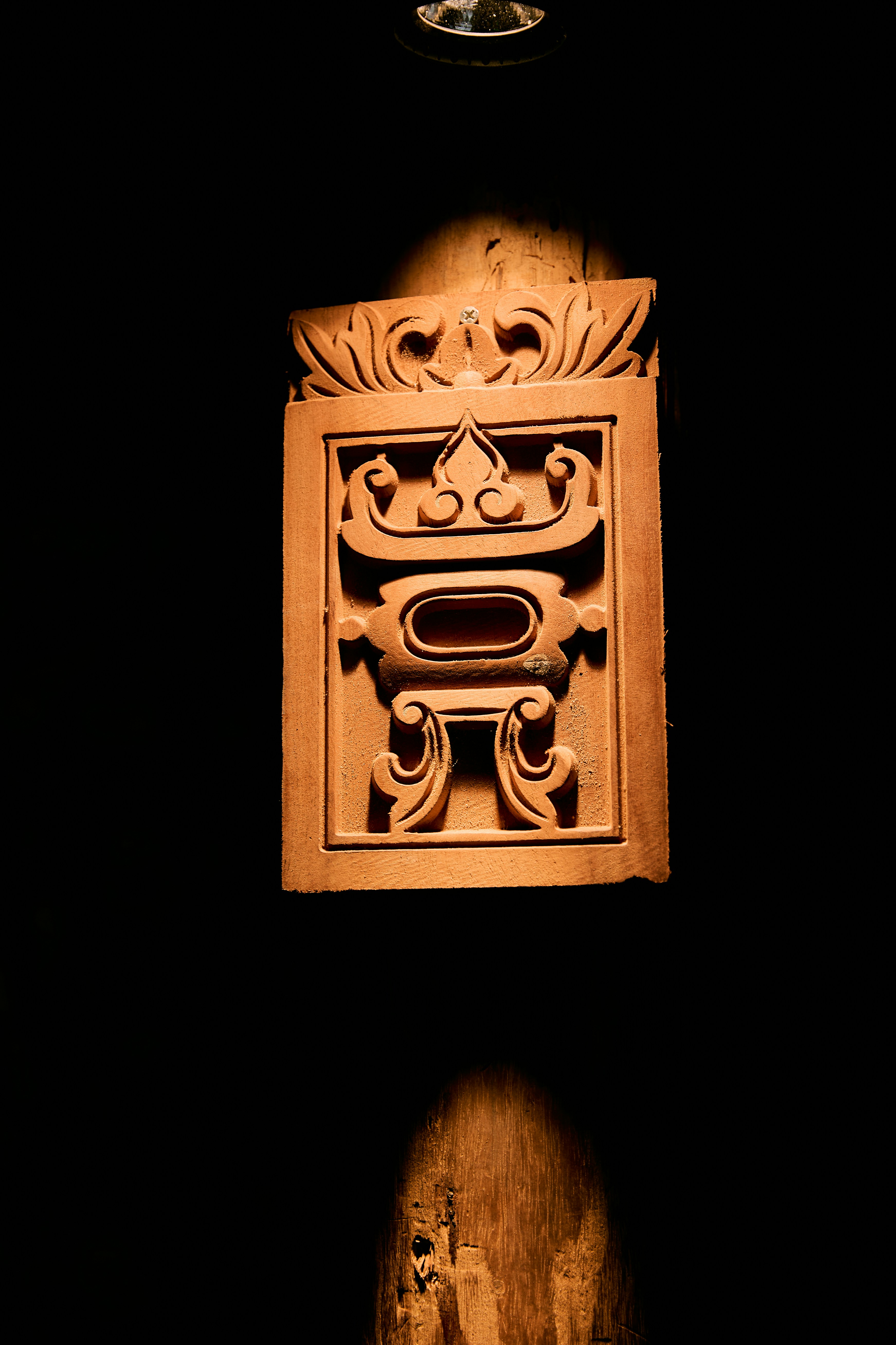 Ornate wood carving illuminated in a dark backdrop