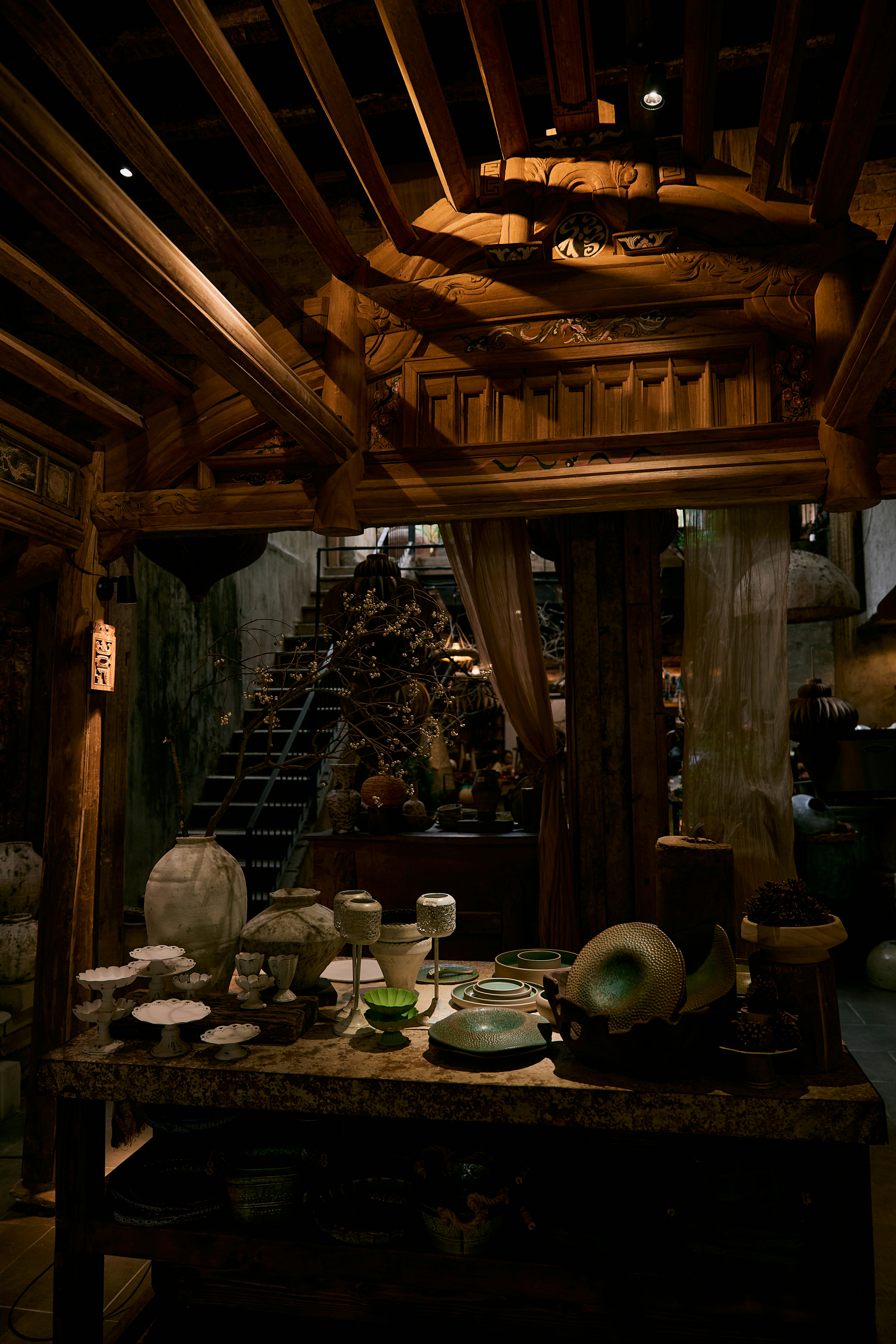 Dimly Lit Shrine Shop: Warm Wood, Ceramic Shards and a Central Table