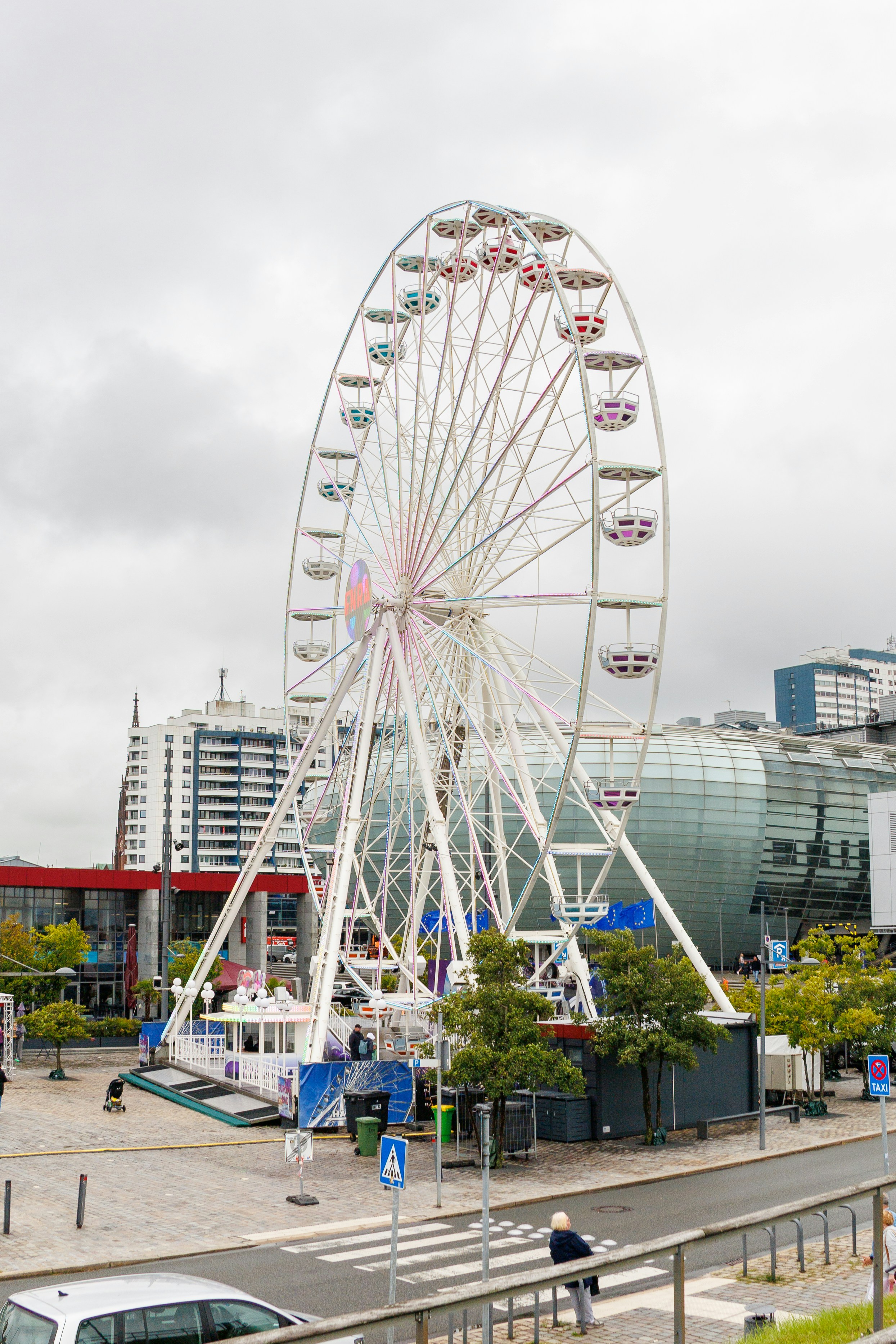 Circular Skies: A Ferris Wheel Overlooking a Modern Plaza