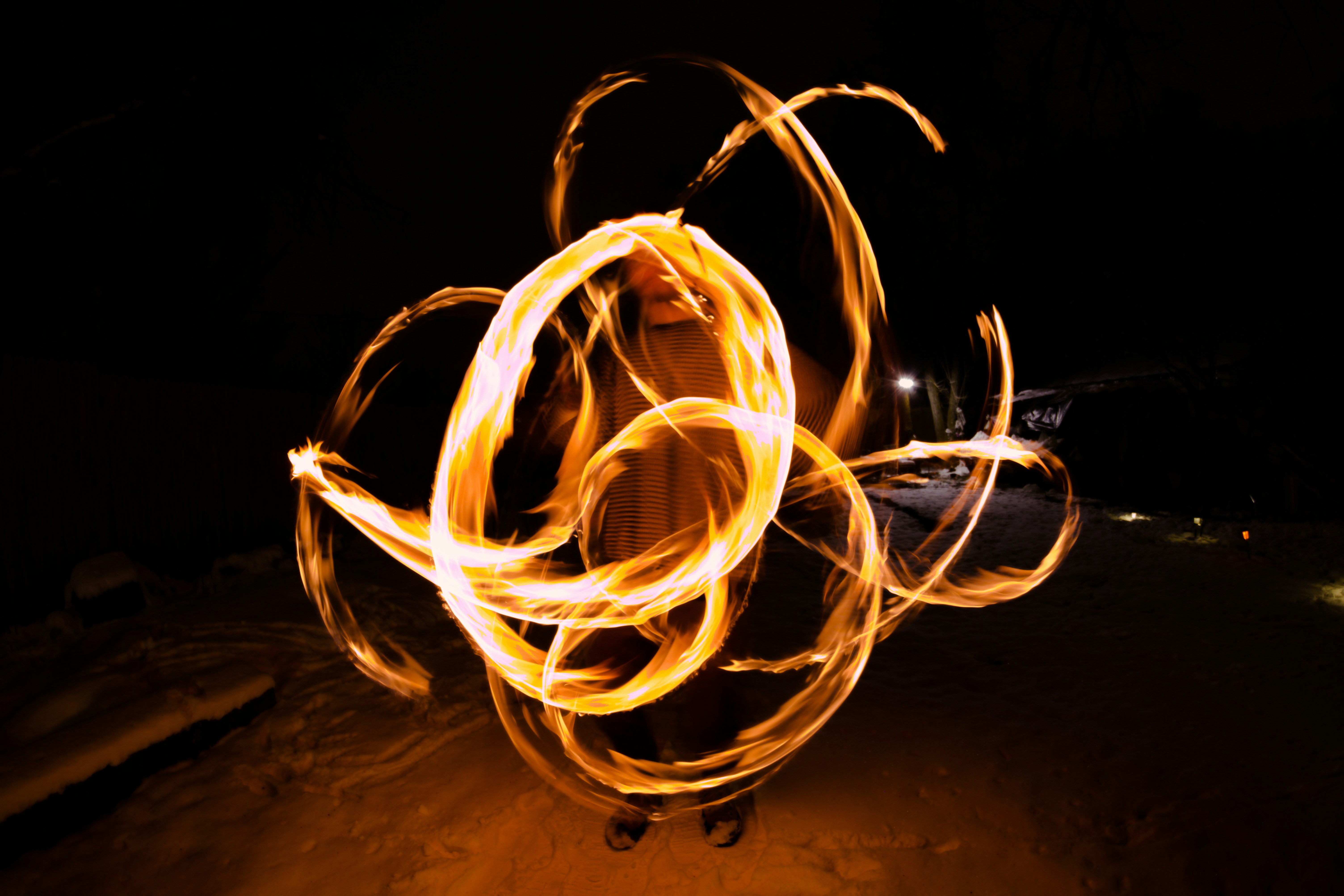 Fire dancers weave glowing loops around a dark, snowy night