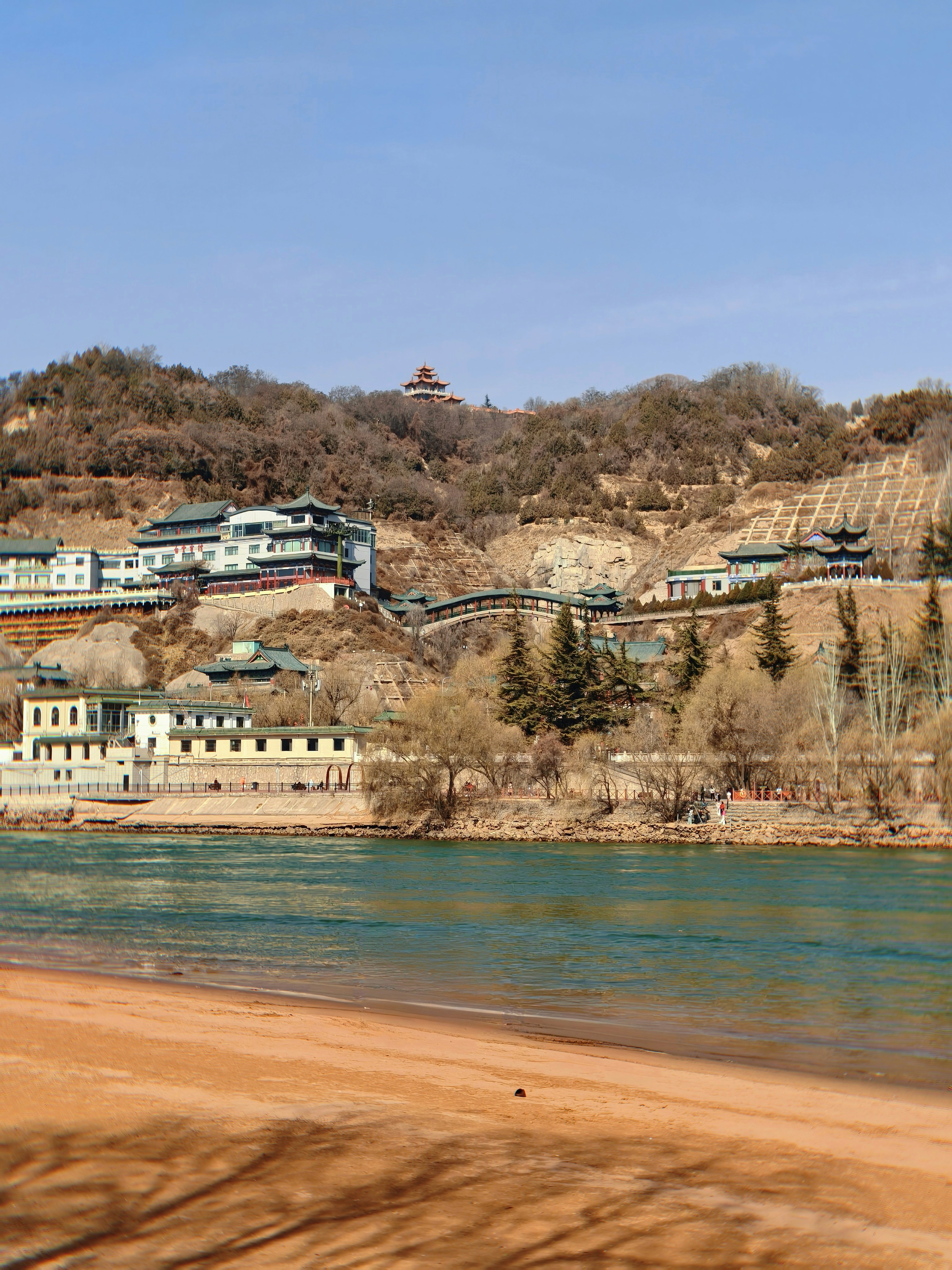 Riverfront buildings on a hillside under a clear sky.