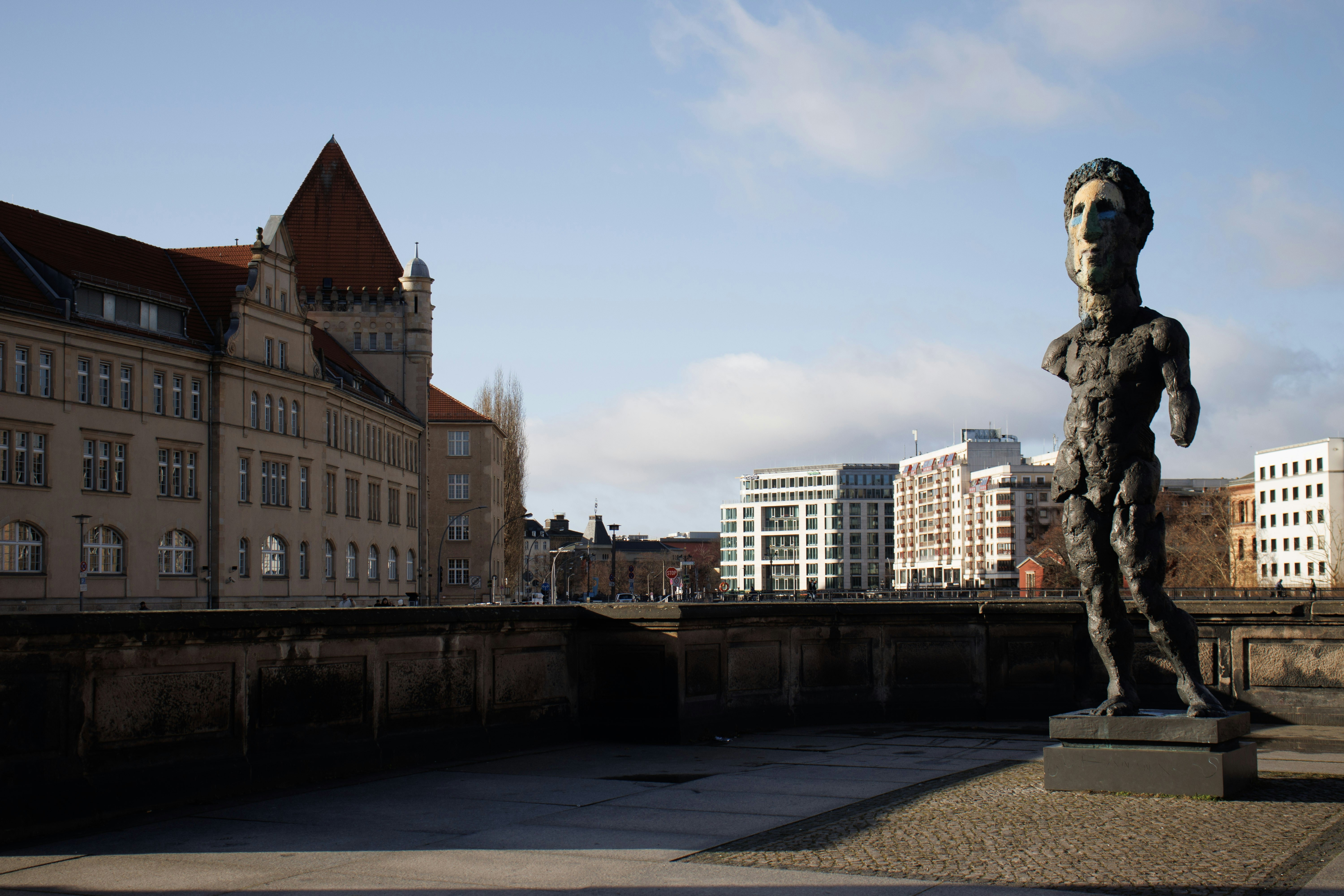 Statue on the Riverside: A Gritty Bronze Sentinel Against a City Backdrop