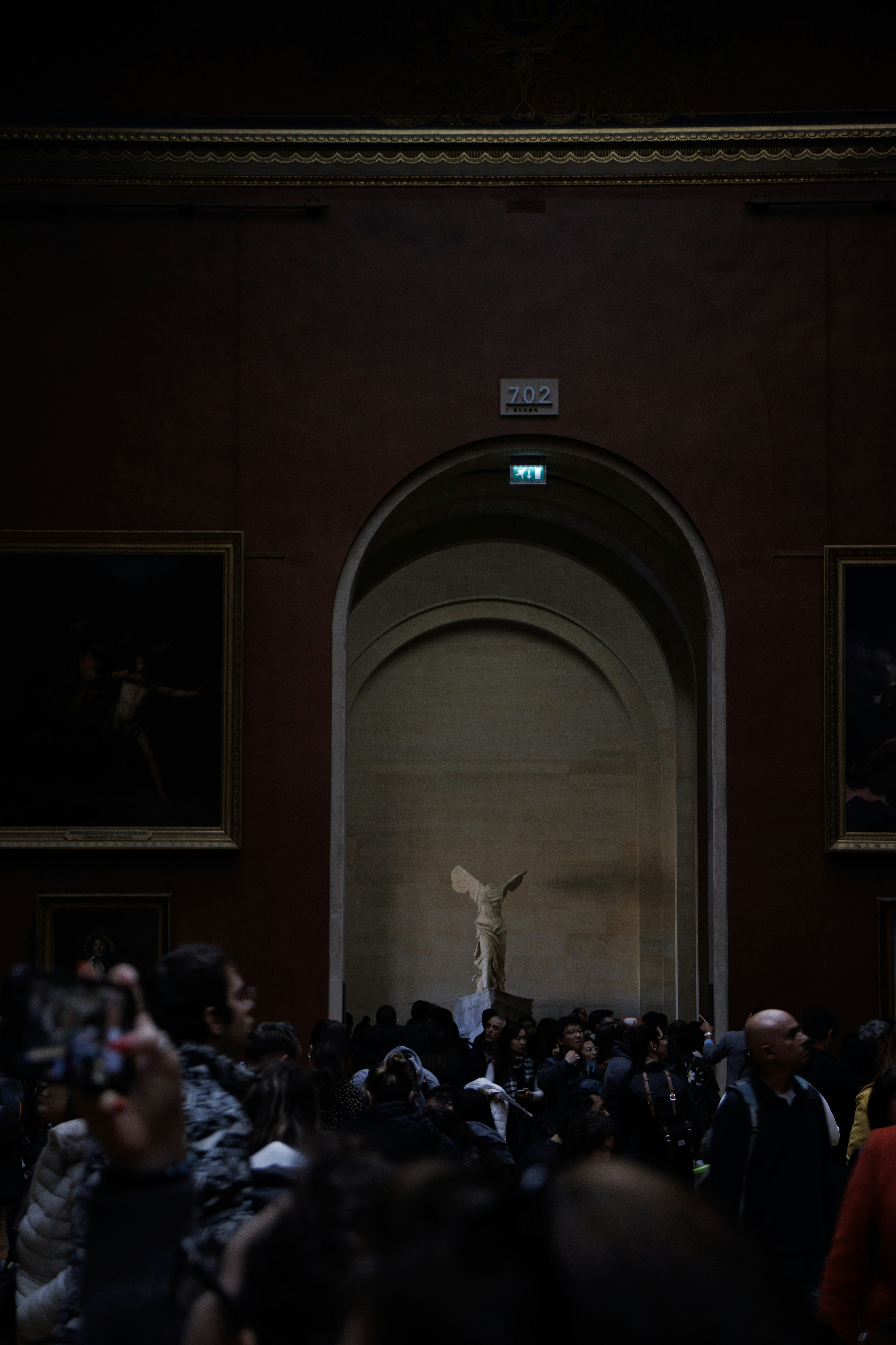 Statue in the Centered Arch: Quiet Amidst the Gallery Crowd