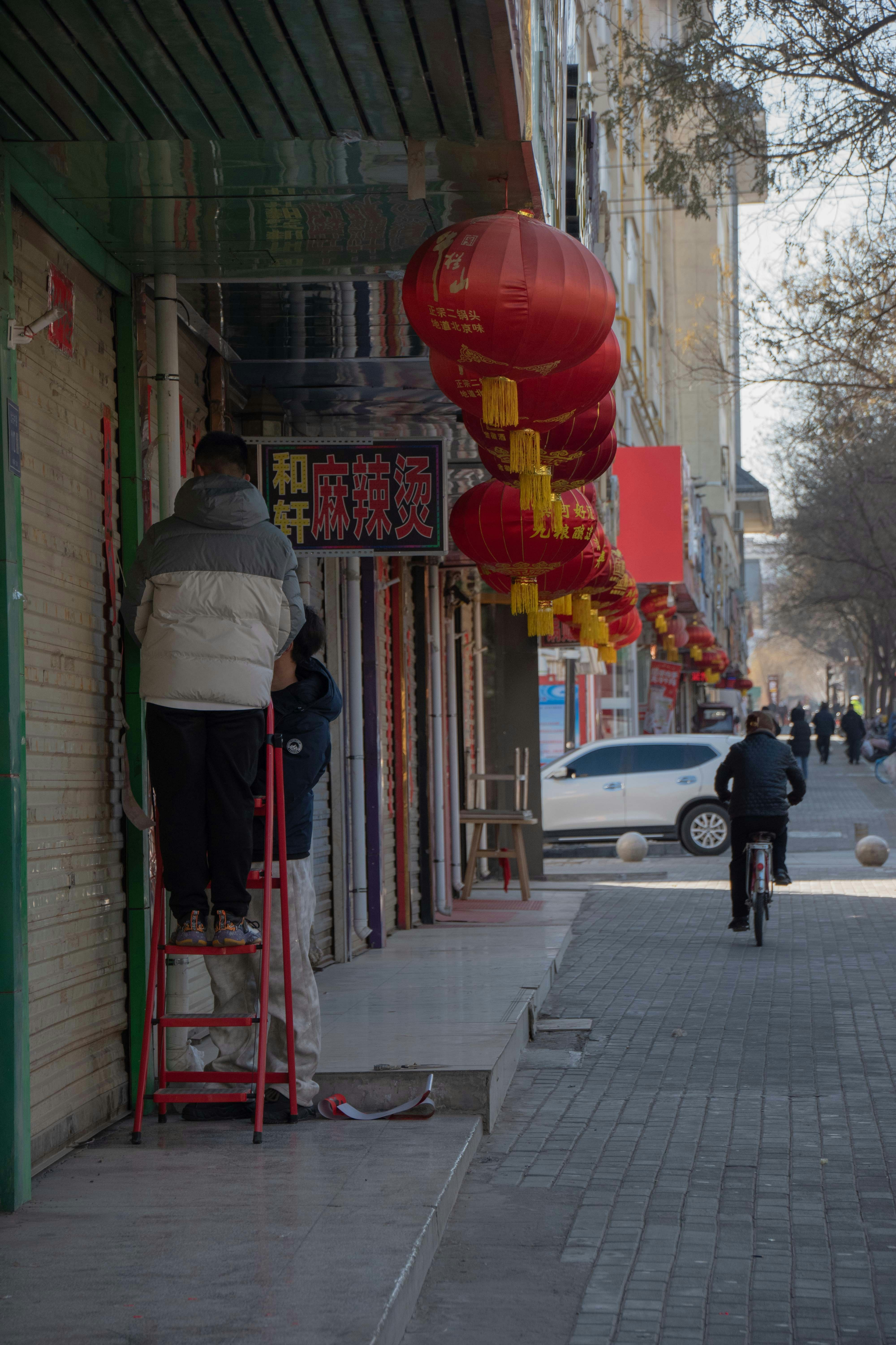 Streetside Lanterns and Ladder Crew Along a Quiet Chinese Shopfront