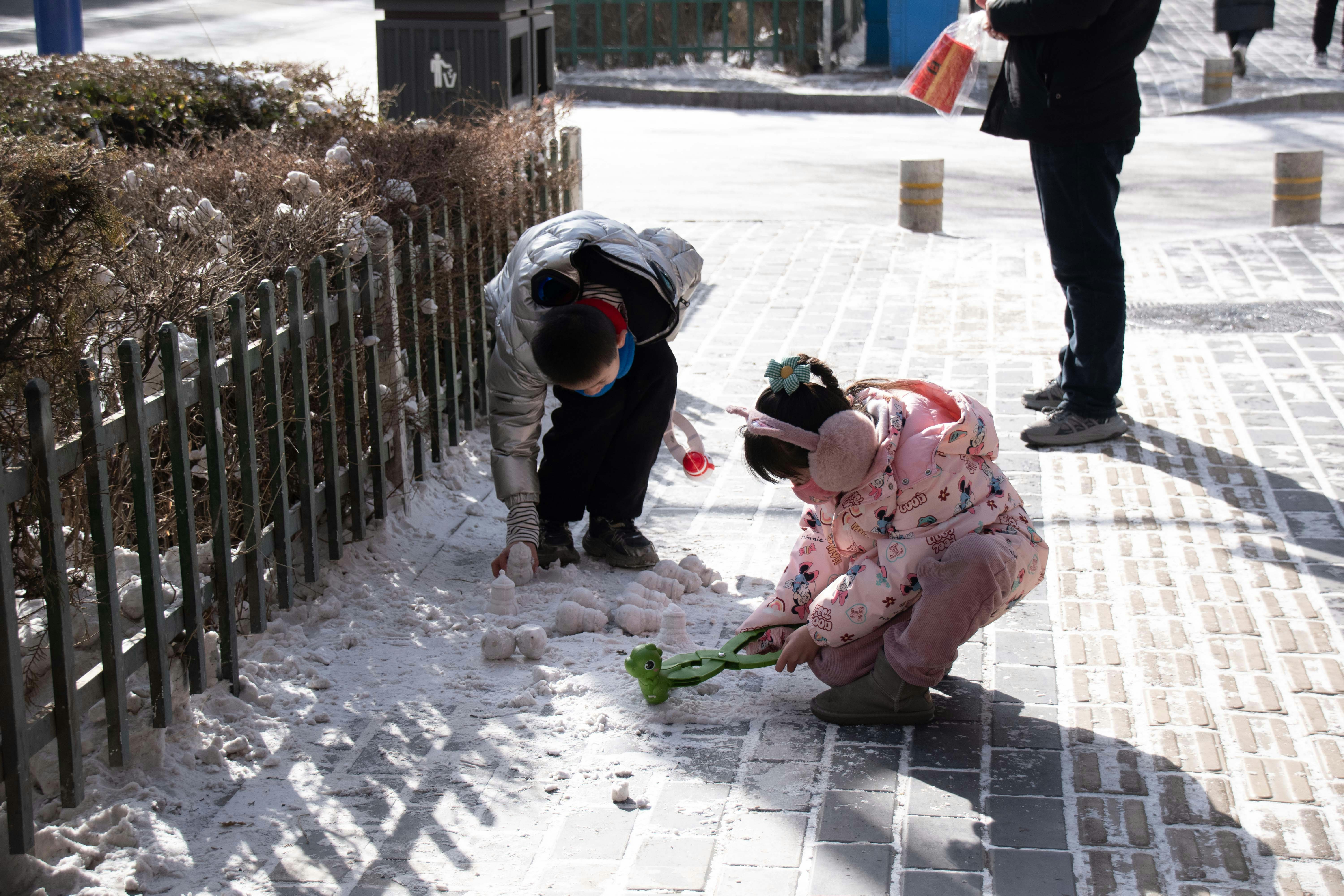 Snowy Sidewalk Sandbox: Kids Crafting Snow on a Cold City Day