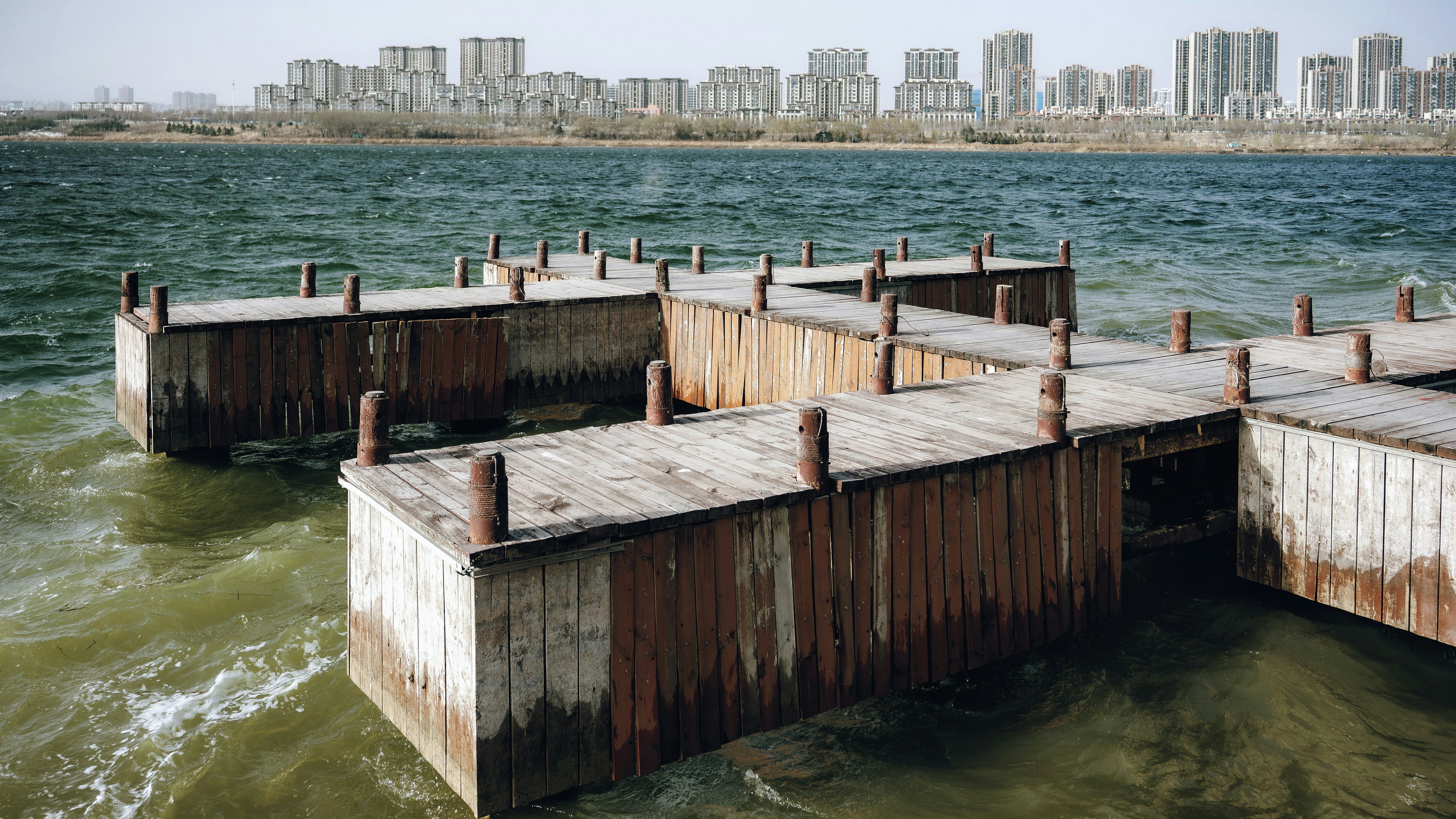 Rusting docks reach toward a distant cityscape