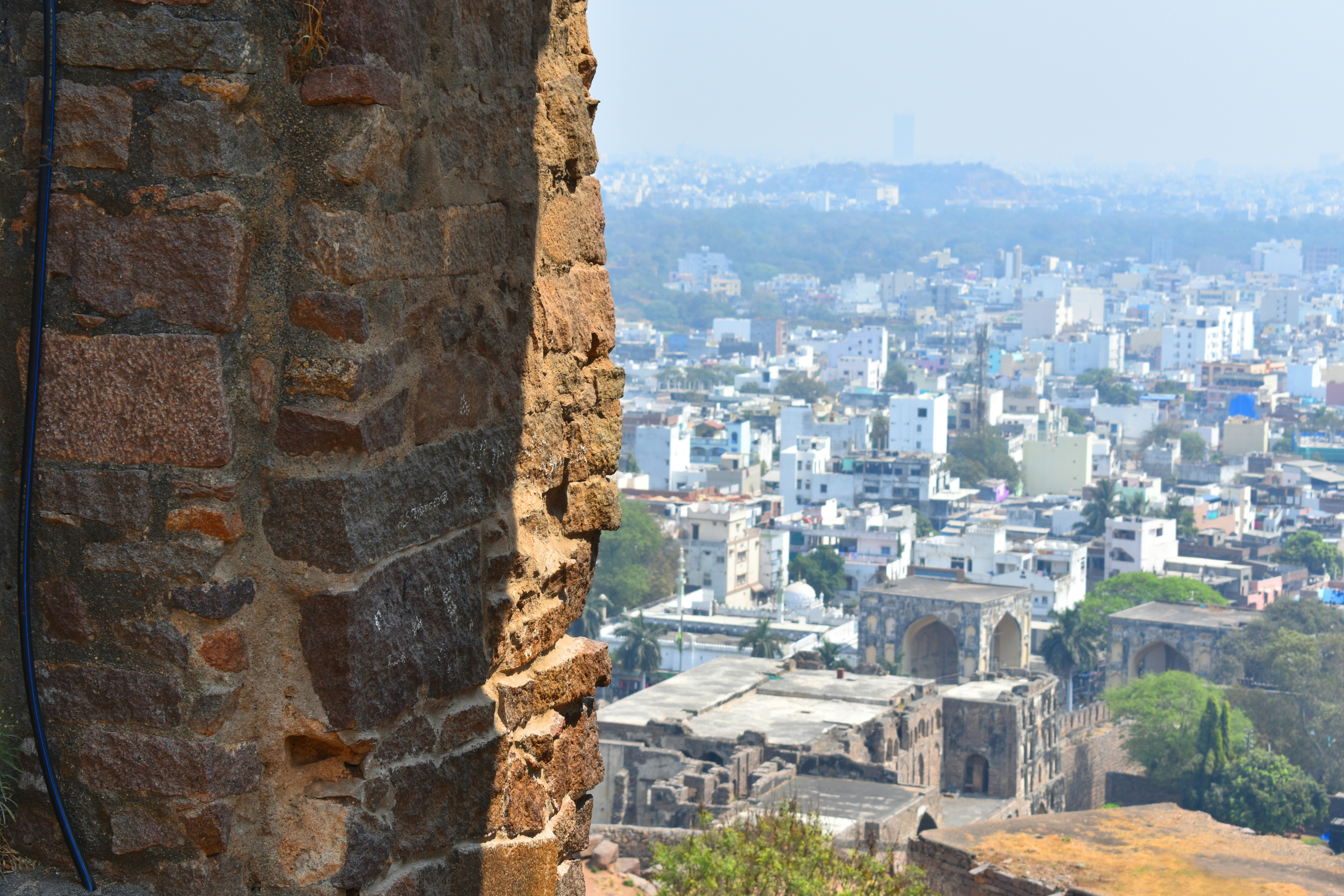 Stone fortress edge overlooks a sunlit, sprawling city