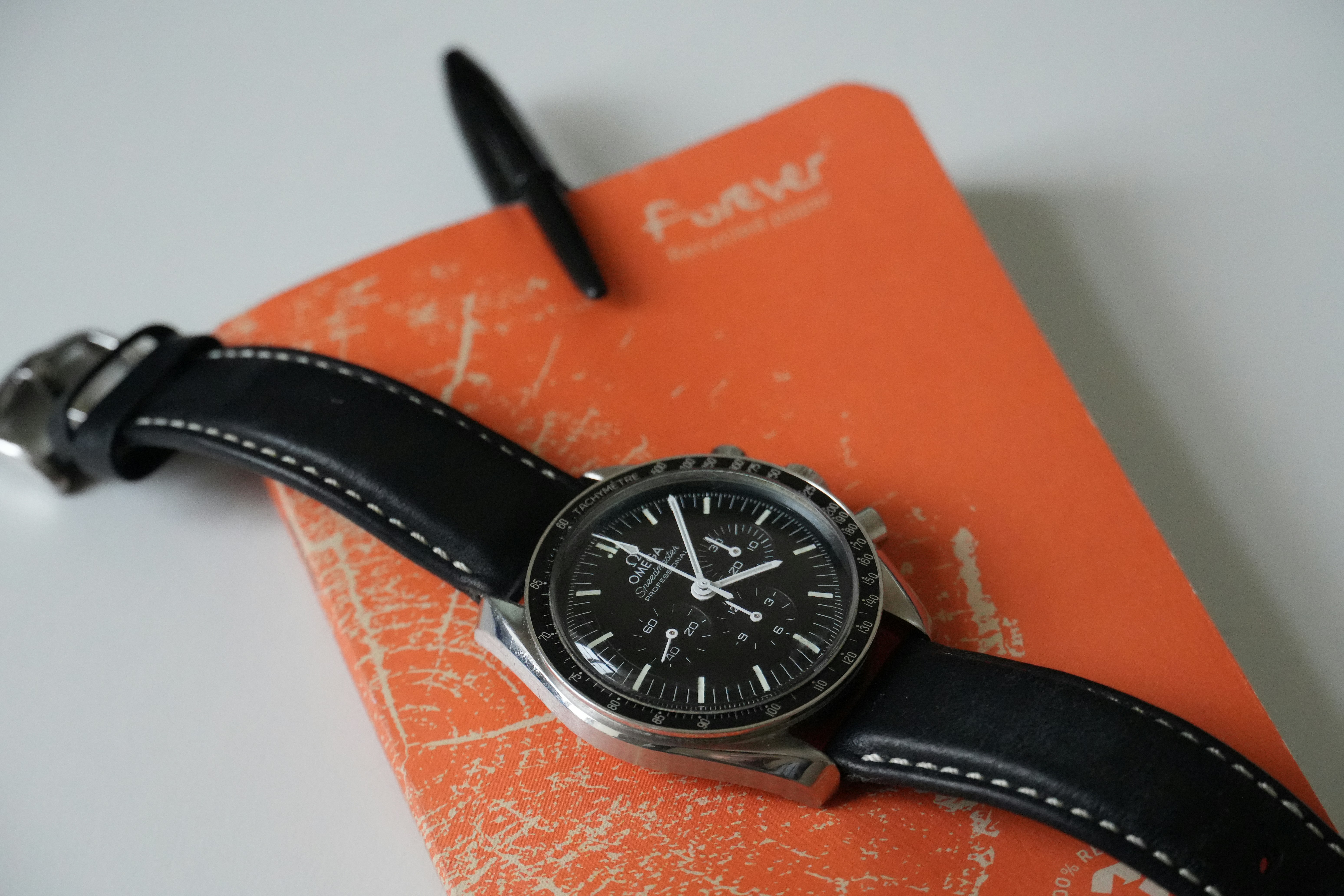 Leather-stitched Chronograph Resting on an Orange Notebook