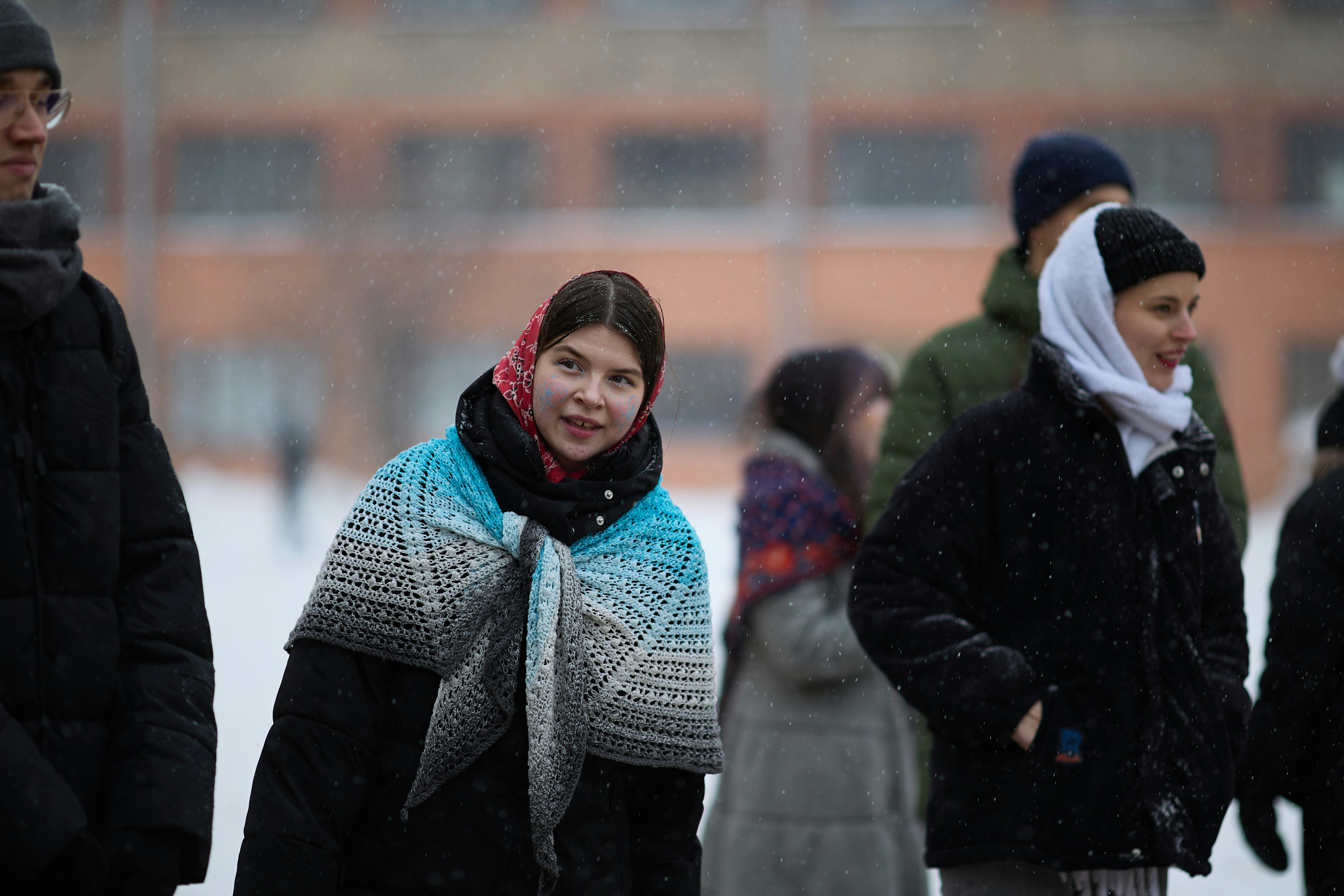 Winter stillness: a girl with a teal shawl amid snowfall