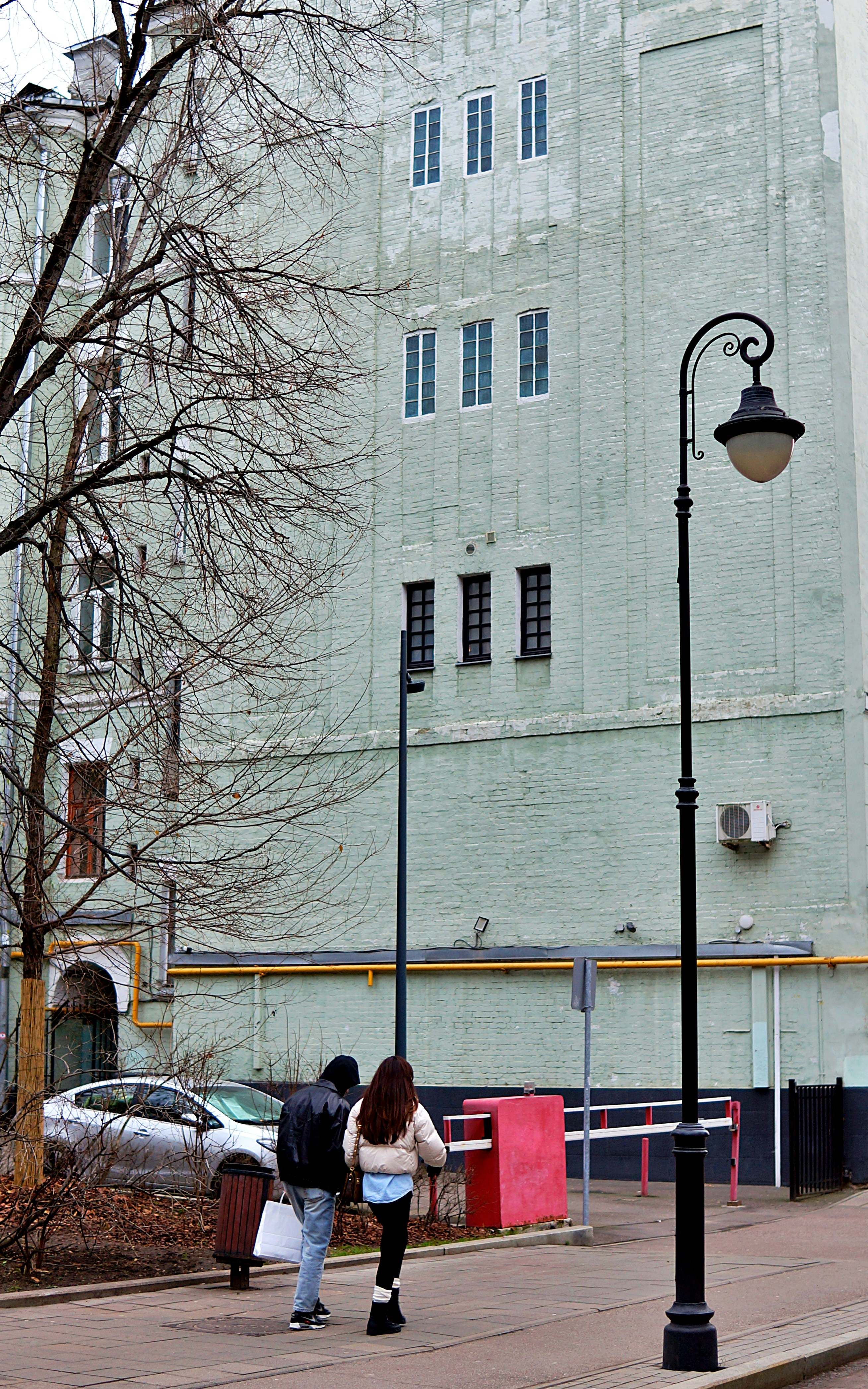 Urban Crossing: Two Wanderers near the Mint-green Facade