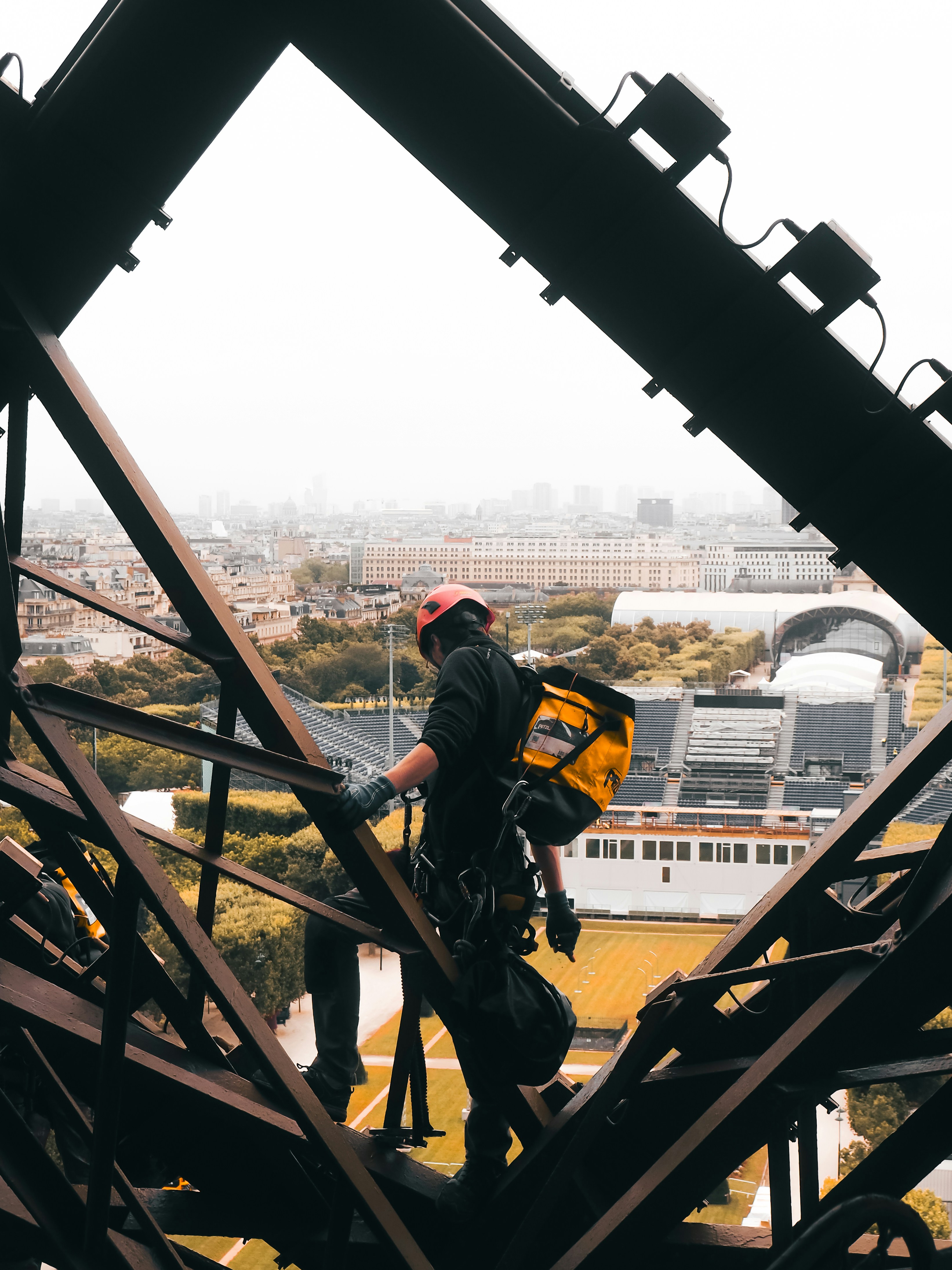 Climber at the Structural Frame: A Cityscape Framed by Iron Lattices
