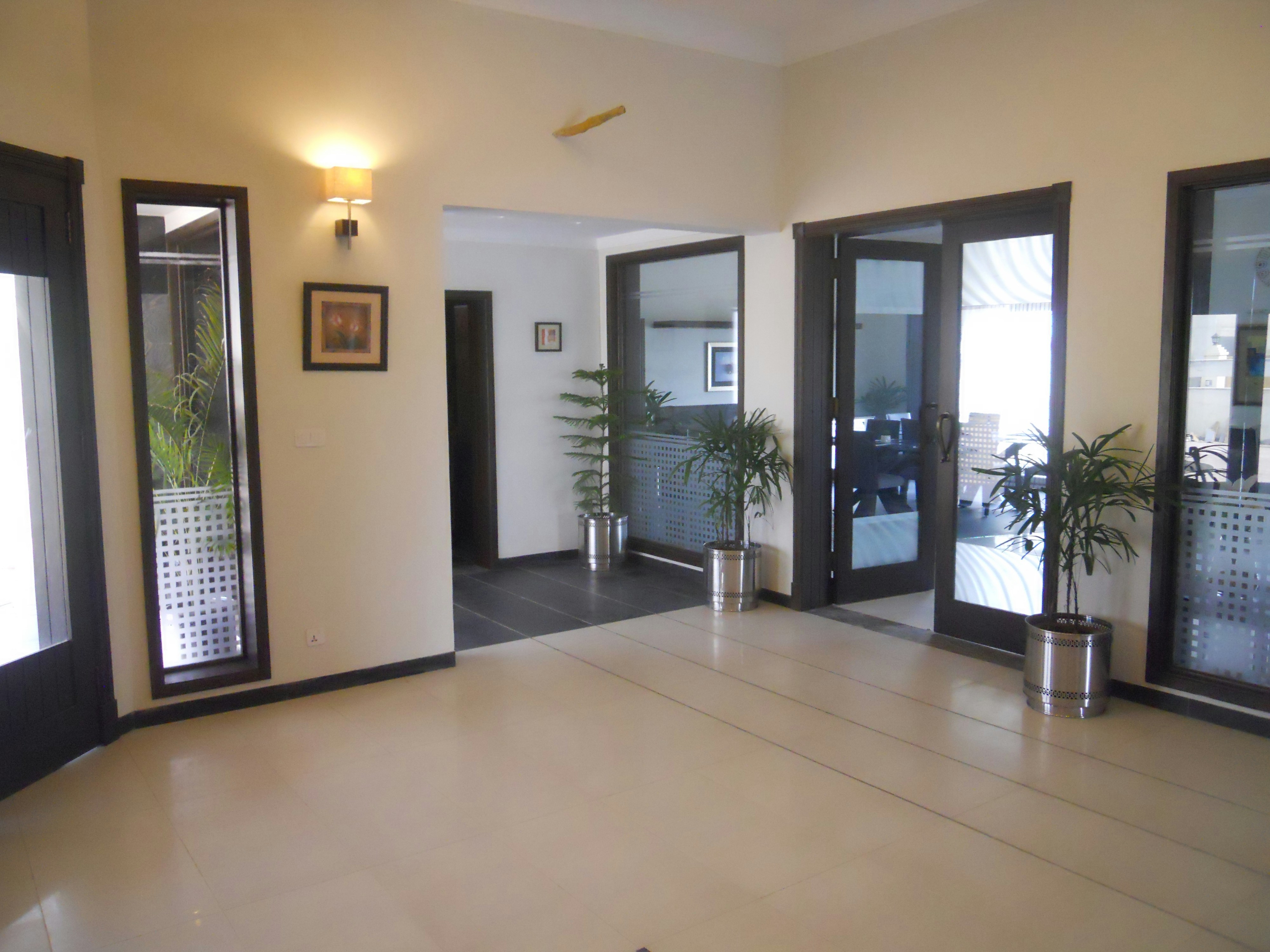 Modern interior hallway with potted plants and glass doors.