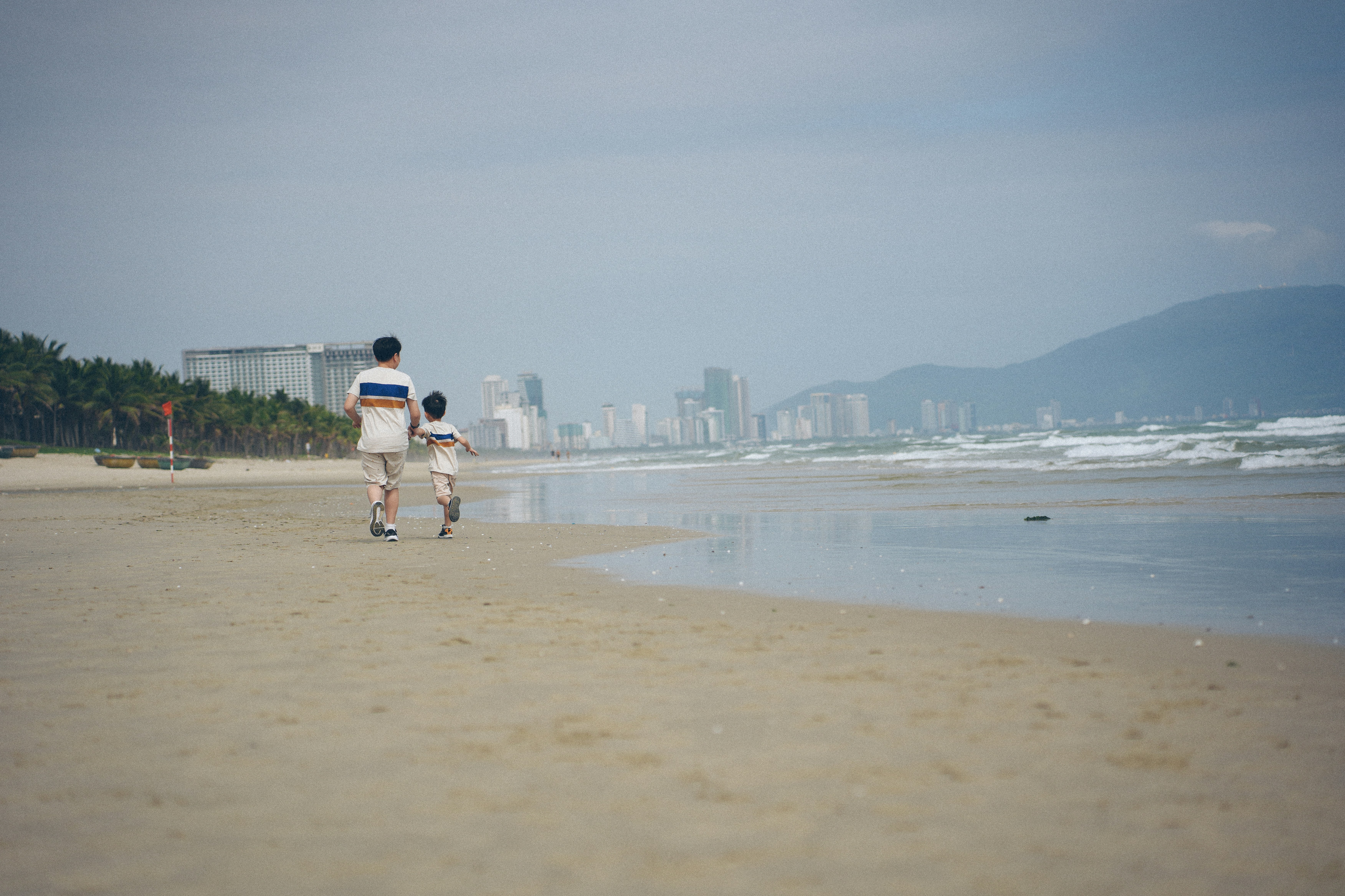 Two Figures Walk the Quiet Edge of the City Beach