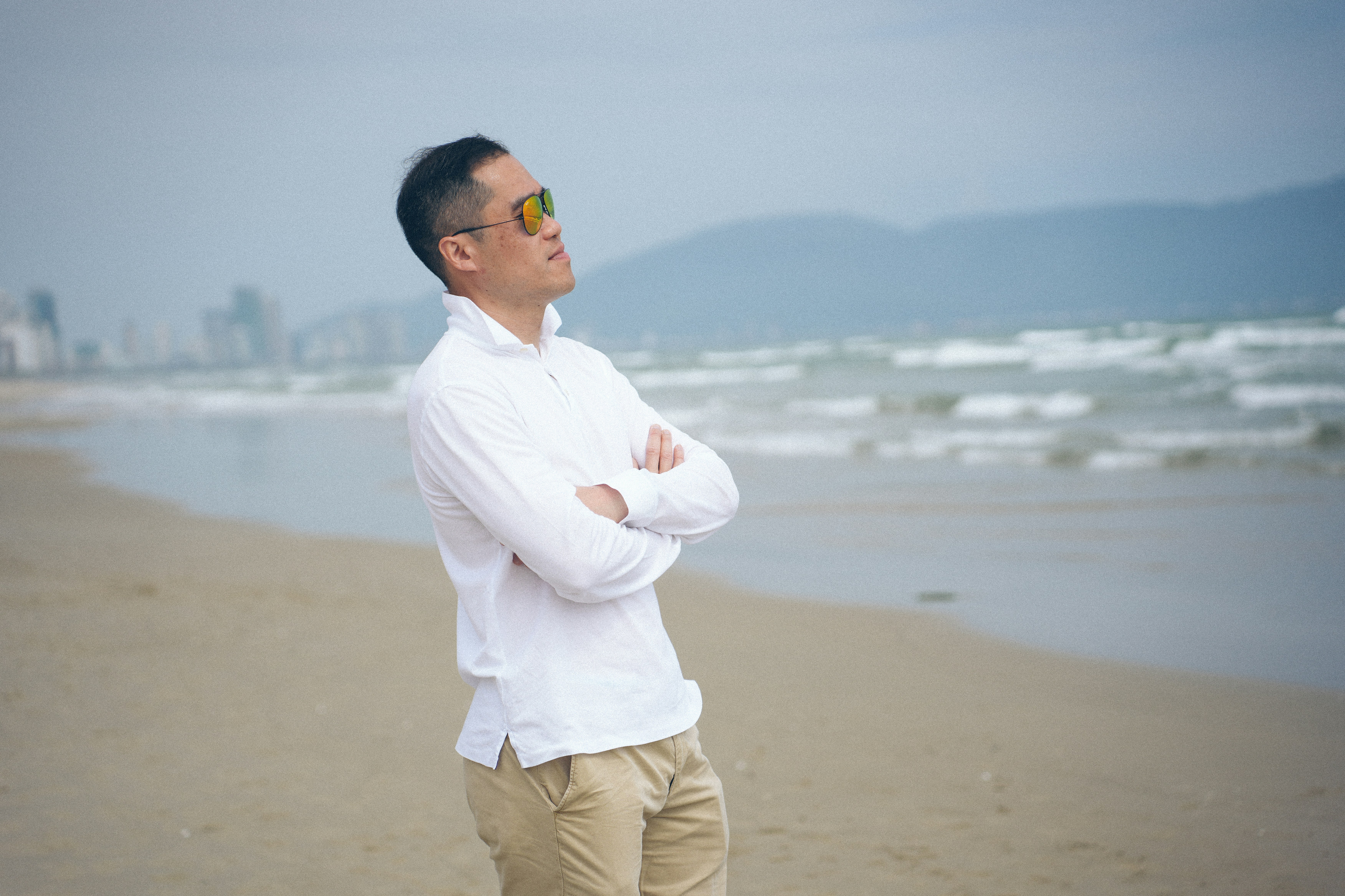 Surfside Confidence: A Man on the Shoreline, Sunglasses Reflecting a Distant City