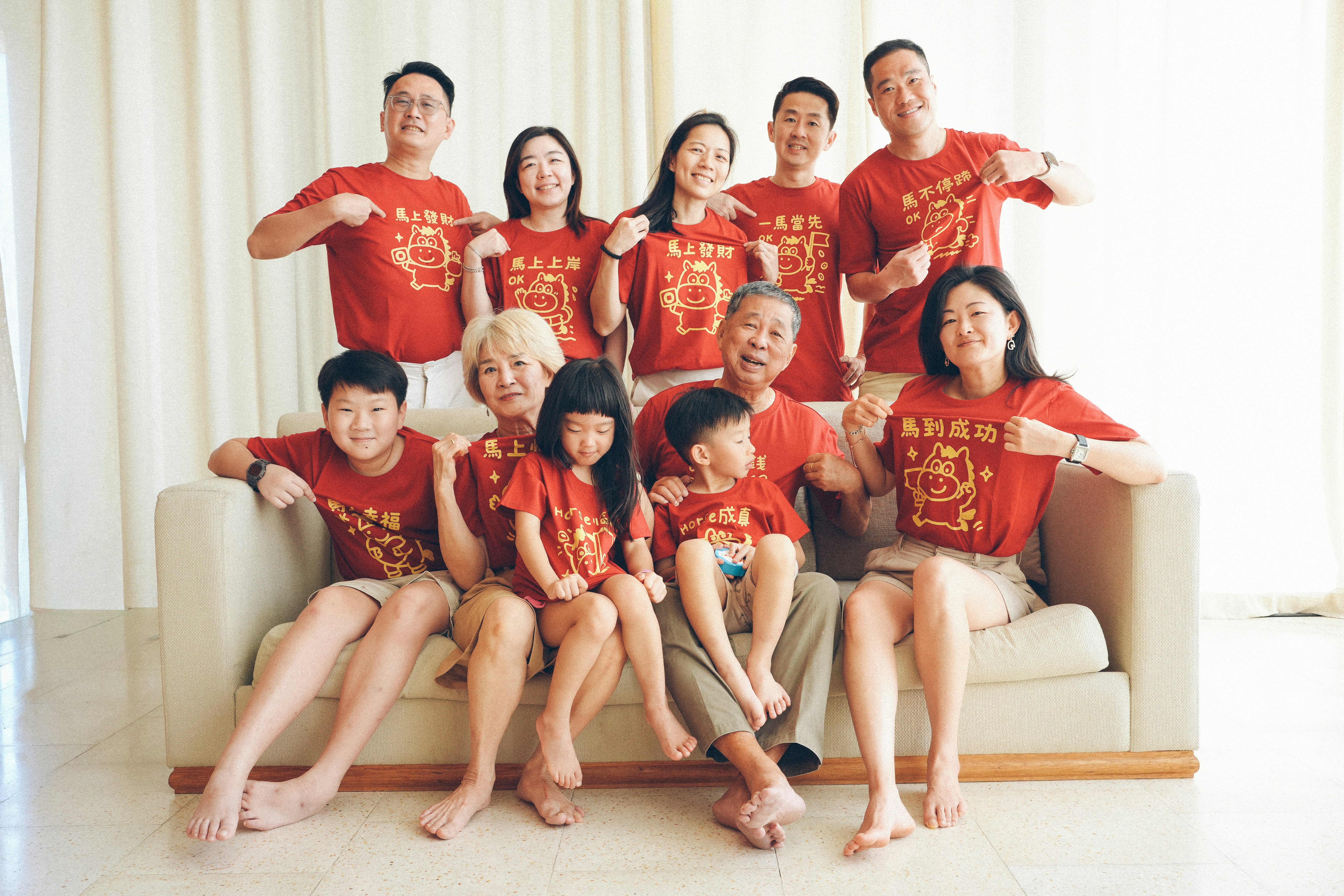Family in coordinated red shirts gathers for a sunlit group portrait