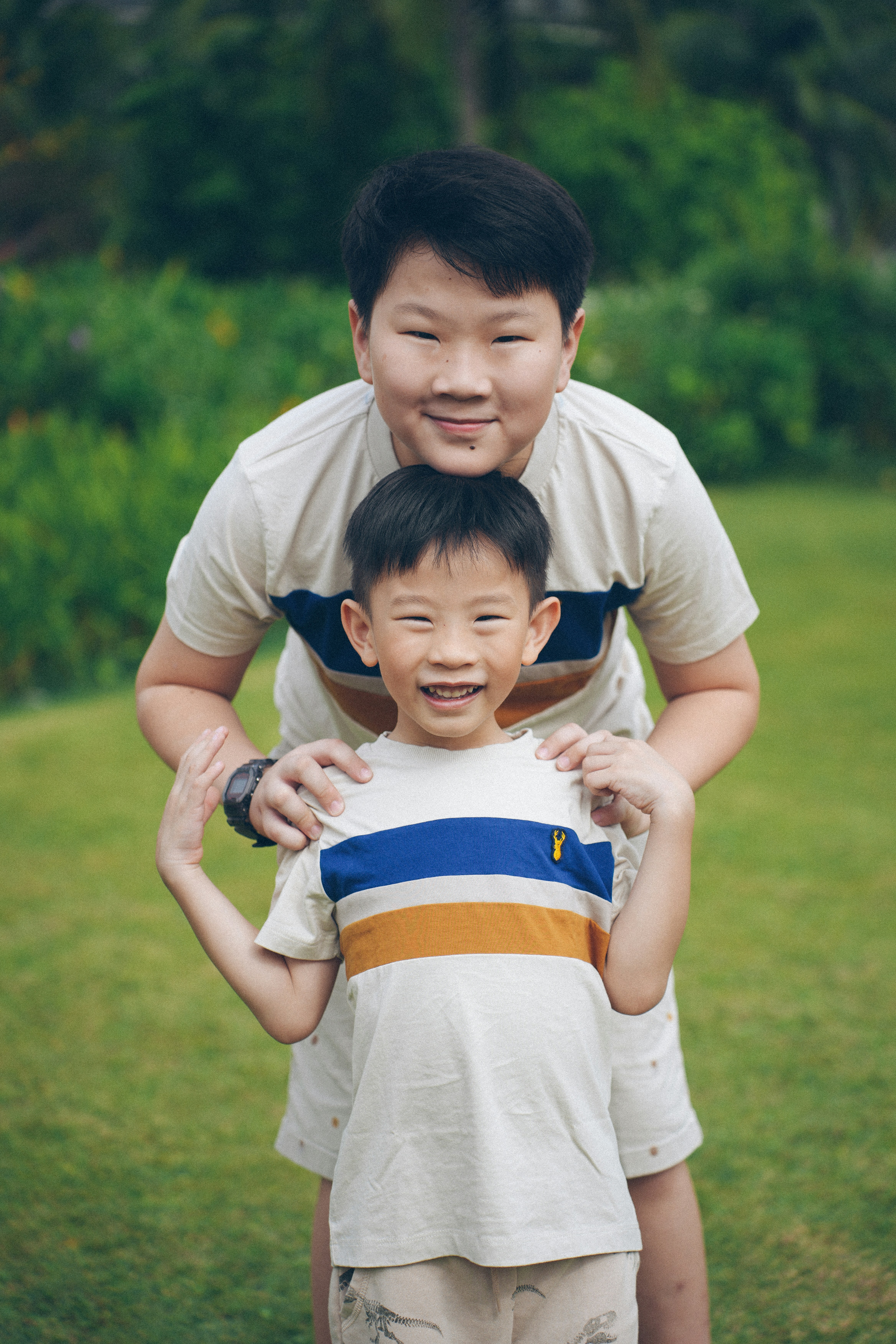 Brotherly hug: two brothers share a playful pose in a sunlit garden