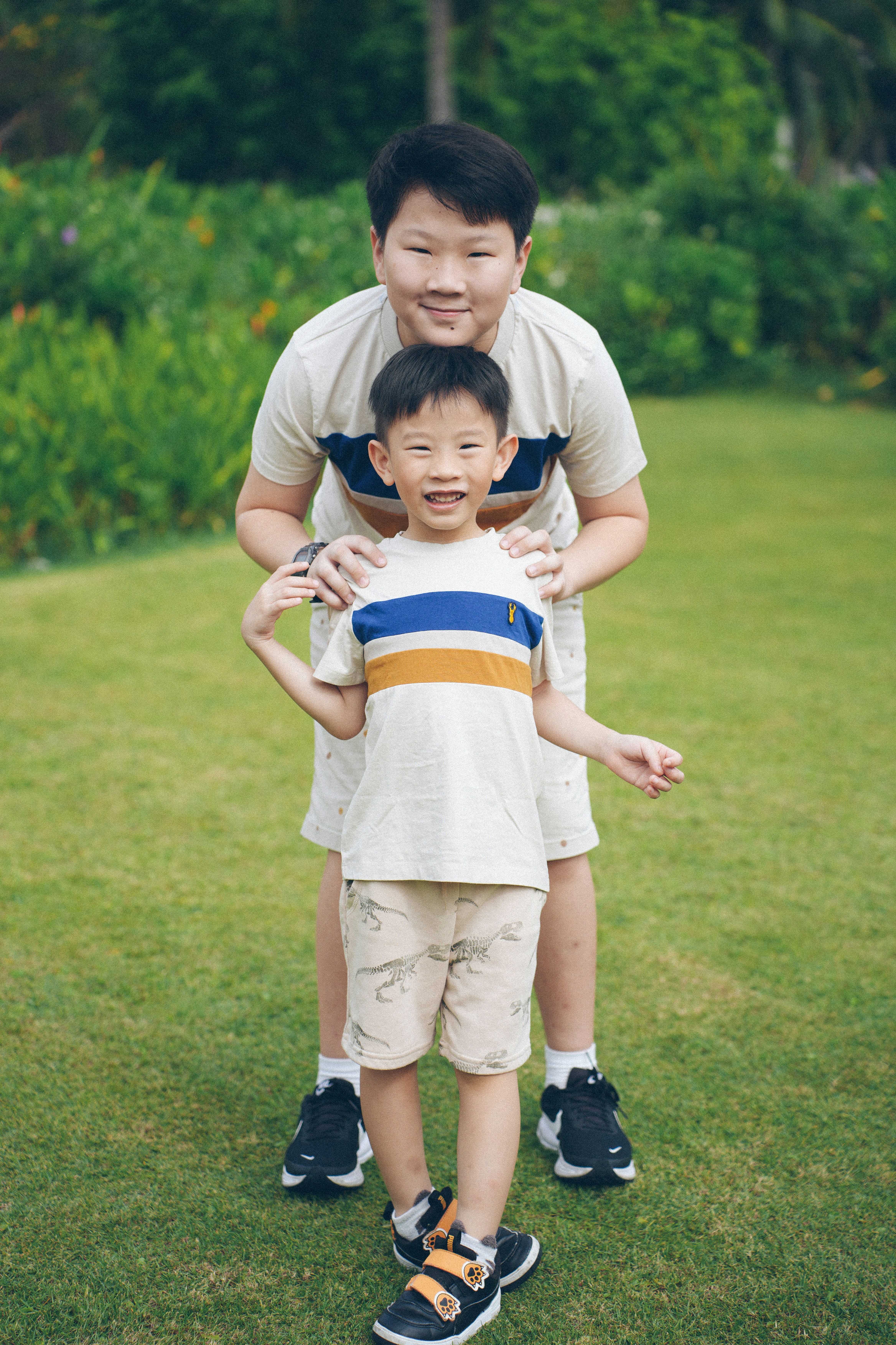 Two brothers in a sunlit park share a playful moment