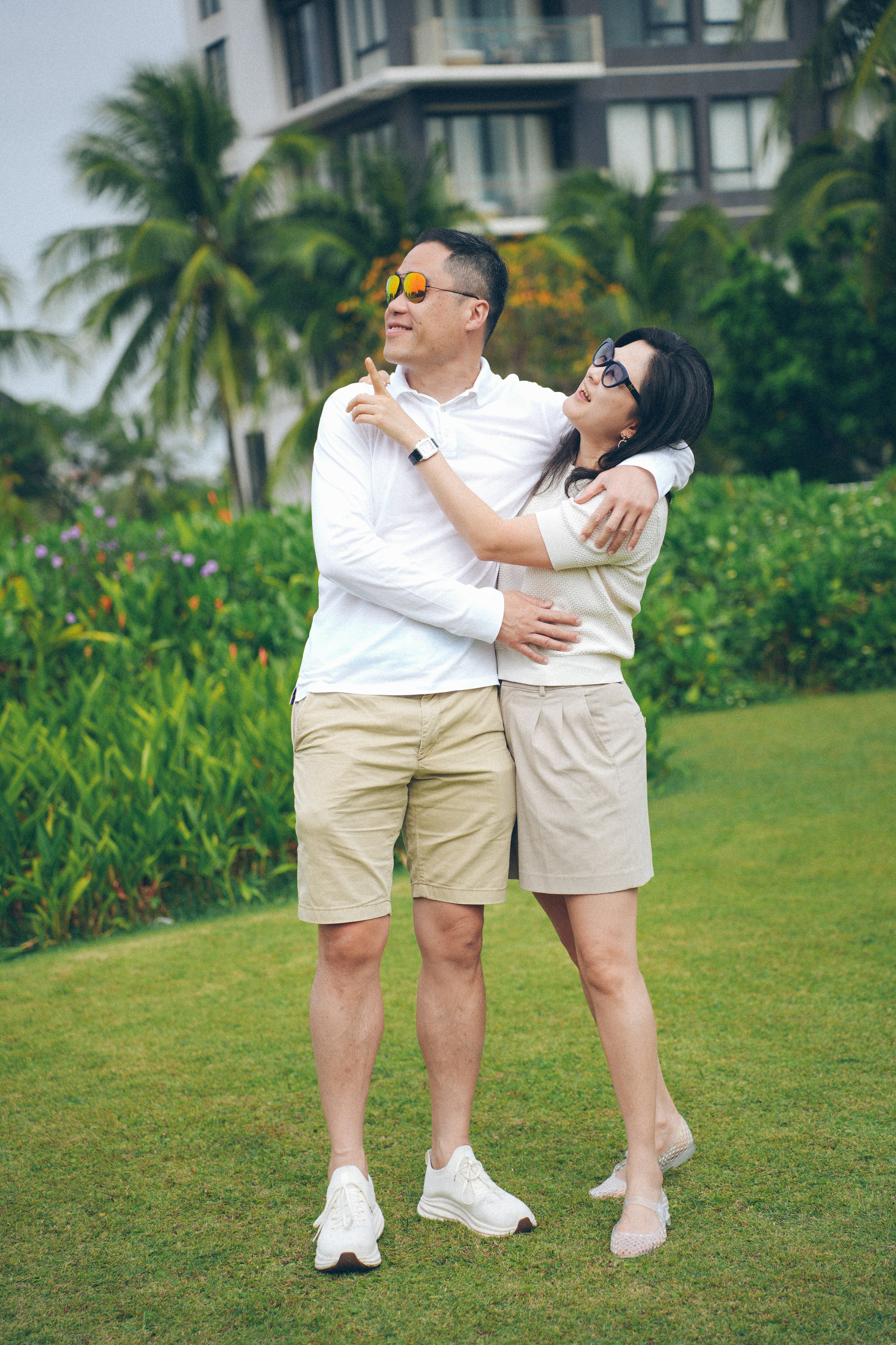 Warm embrace under tropical bokeh: a couple anchors a sunlit garden moment