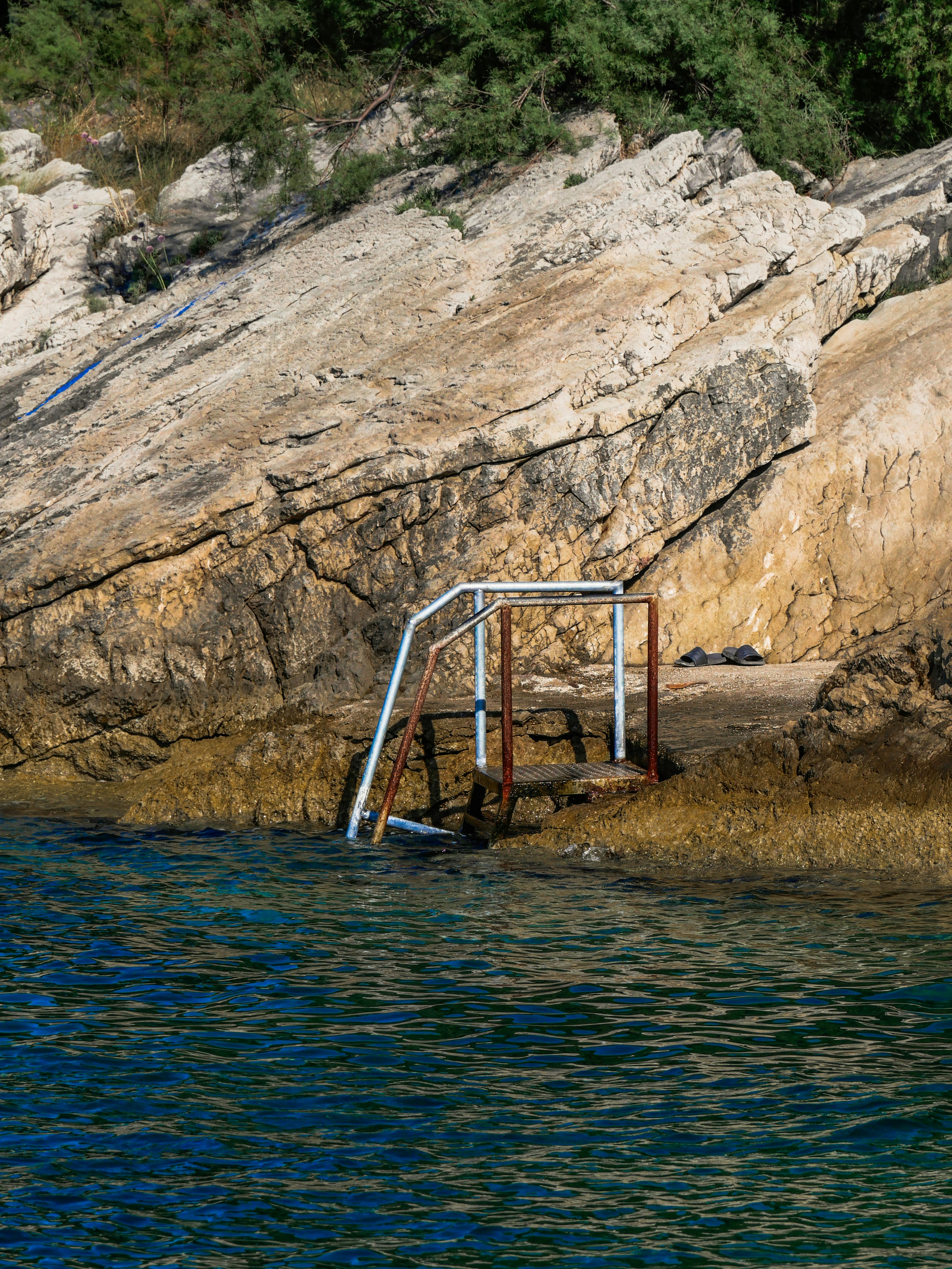 Weathered steps into the sea: a small ladder ascending from the rocks
