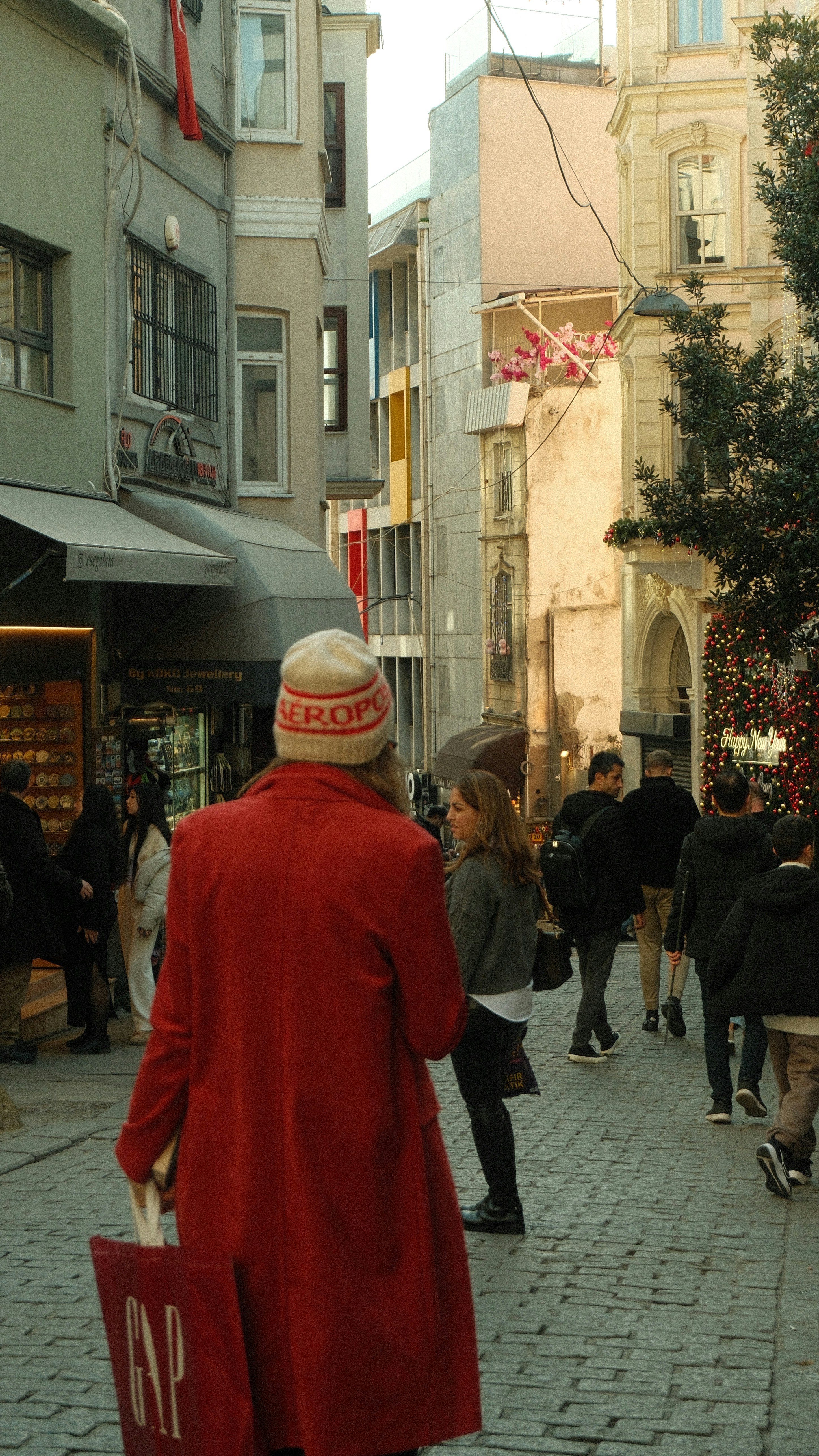 Red Coat in a Cobbled Street: A Street Scene with Shoppers