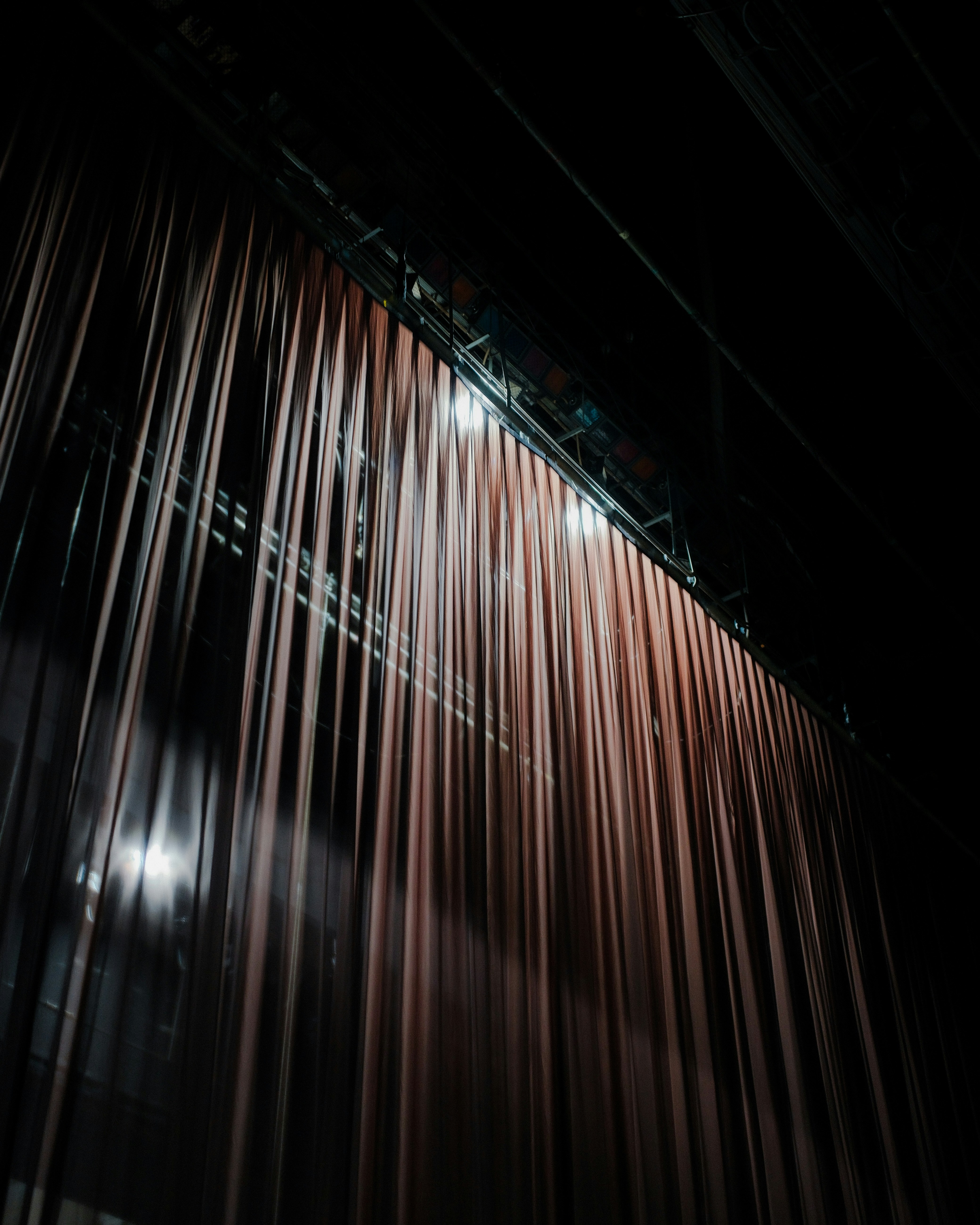 A stage curtain hangs closed in a dark theater.