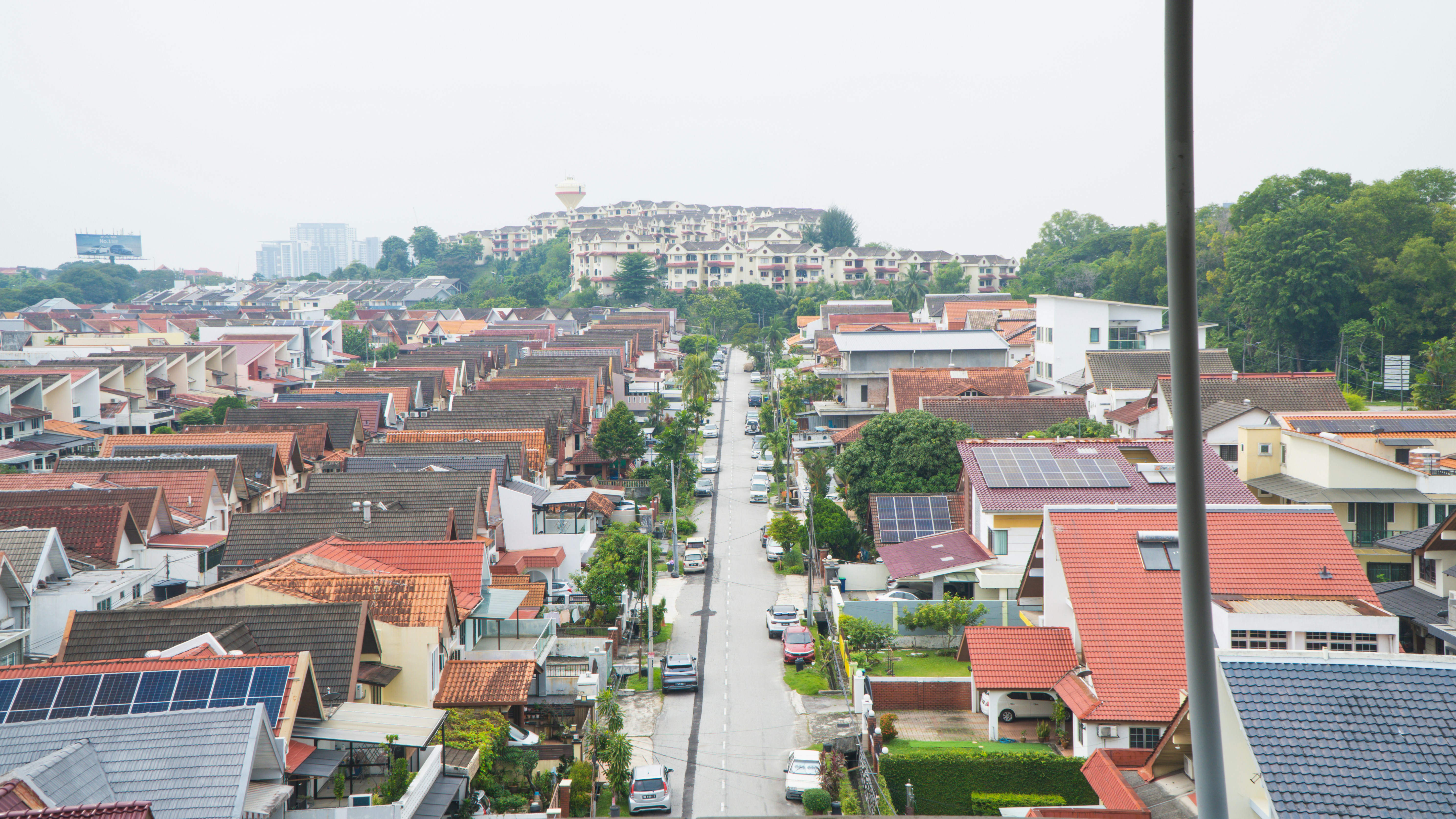 Aerial View of a Sunlit Suburban Avenue Bounded by Colorful Rooftops