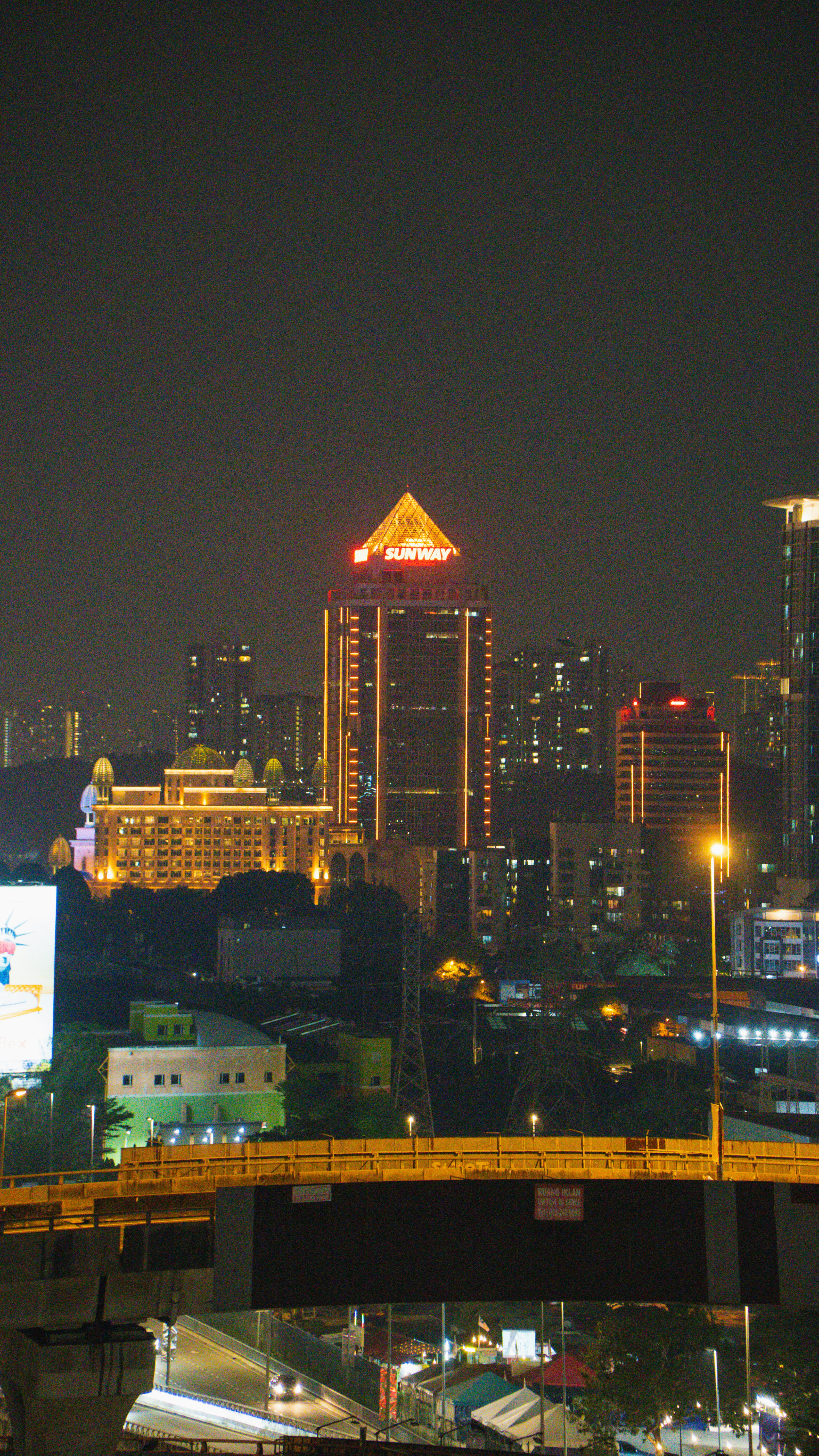 Night Skyline with Lit Pyramid-topped Tower Over a Concrete Bridge