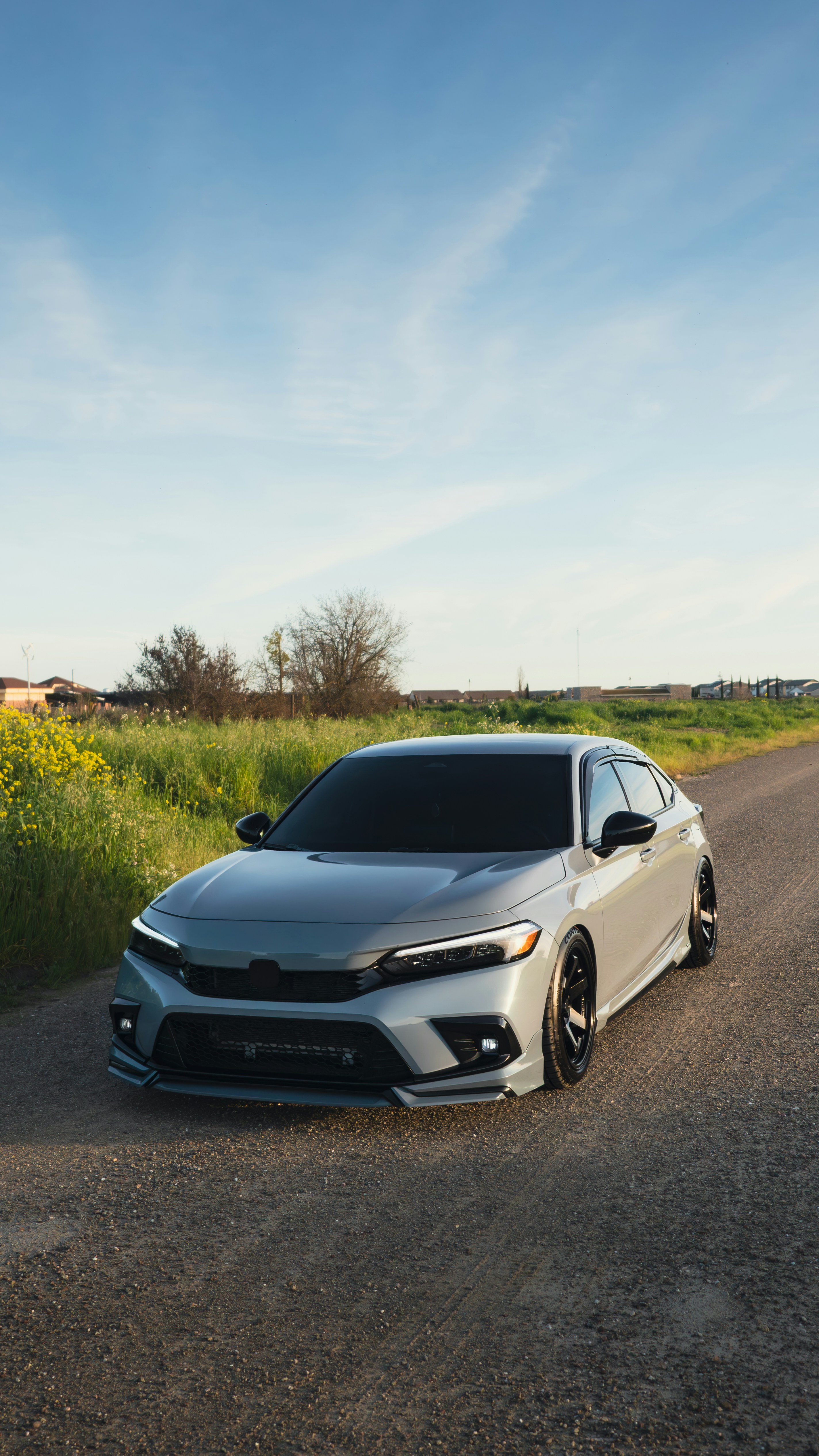 Silver sedan on a rural road under a calm blue sky