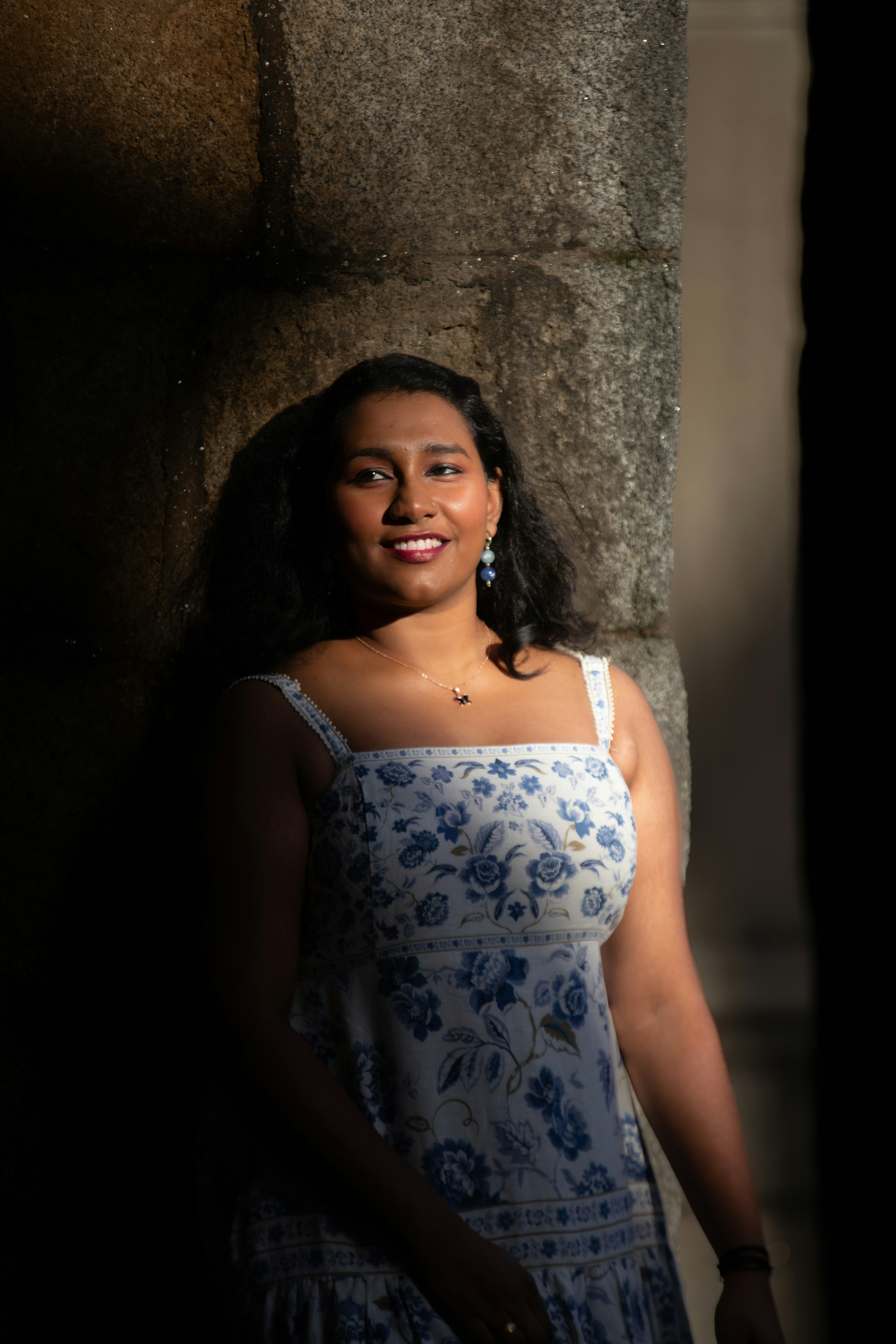 Portrait in Shadow and Light: Woman in Blue Floral Dress at a Stone Arch
