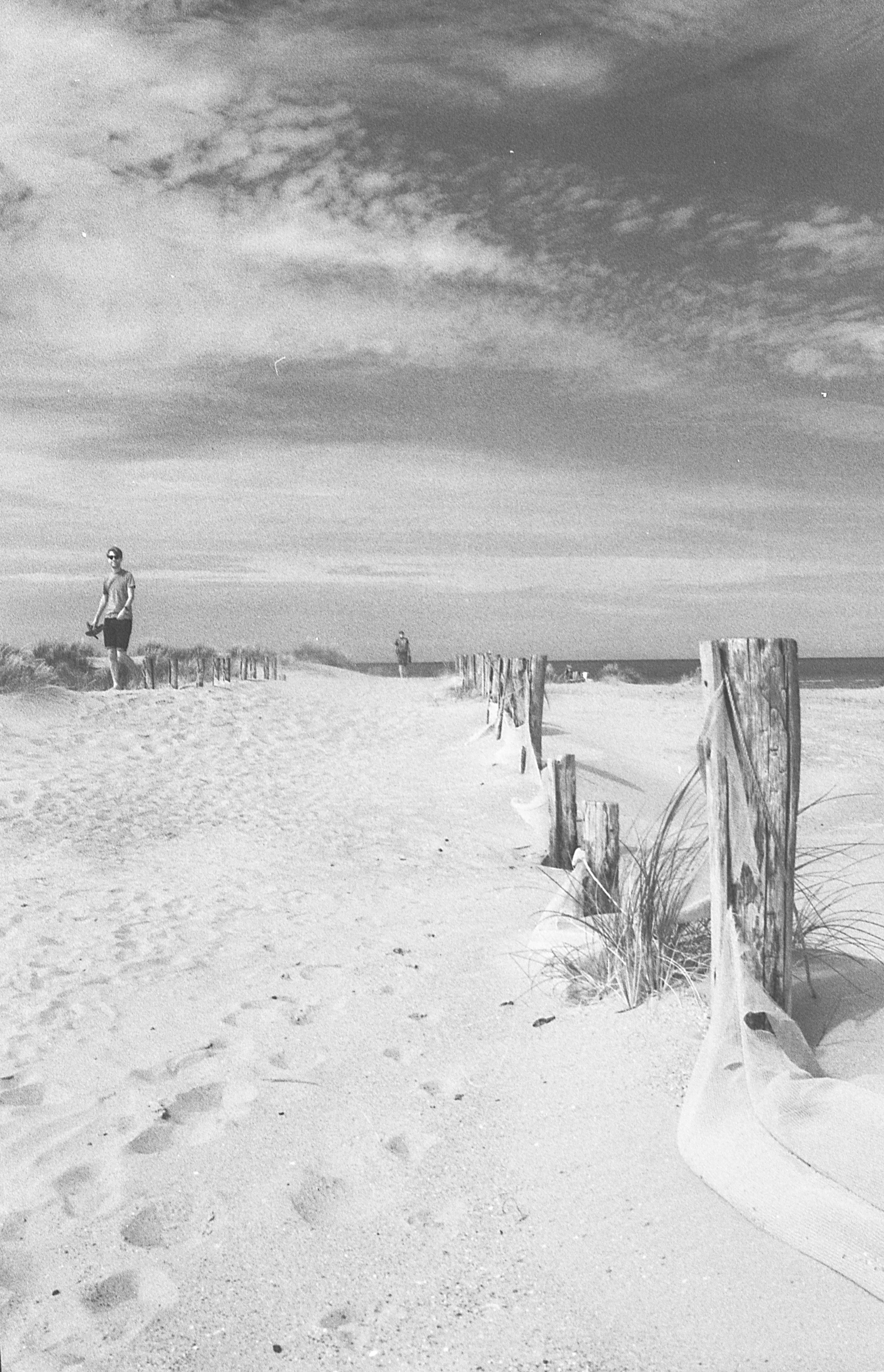 Man standing on a sandy path by the ocean.