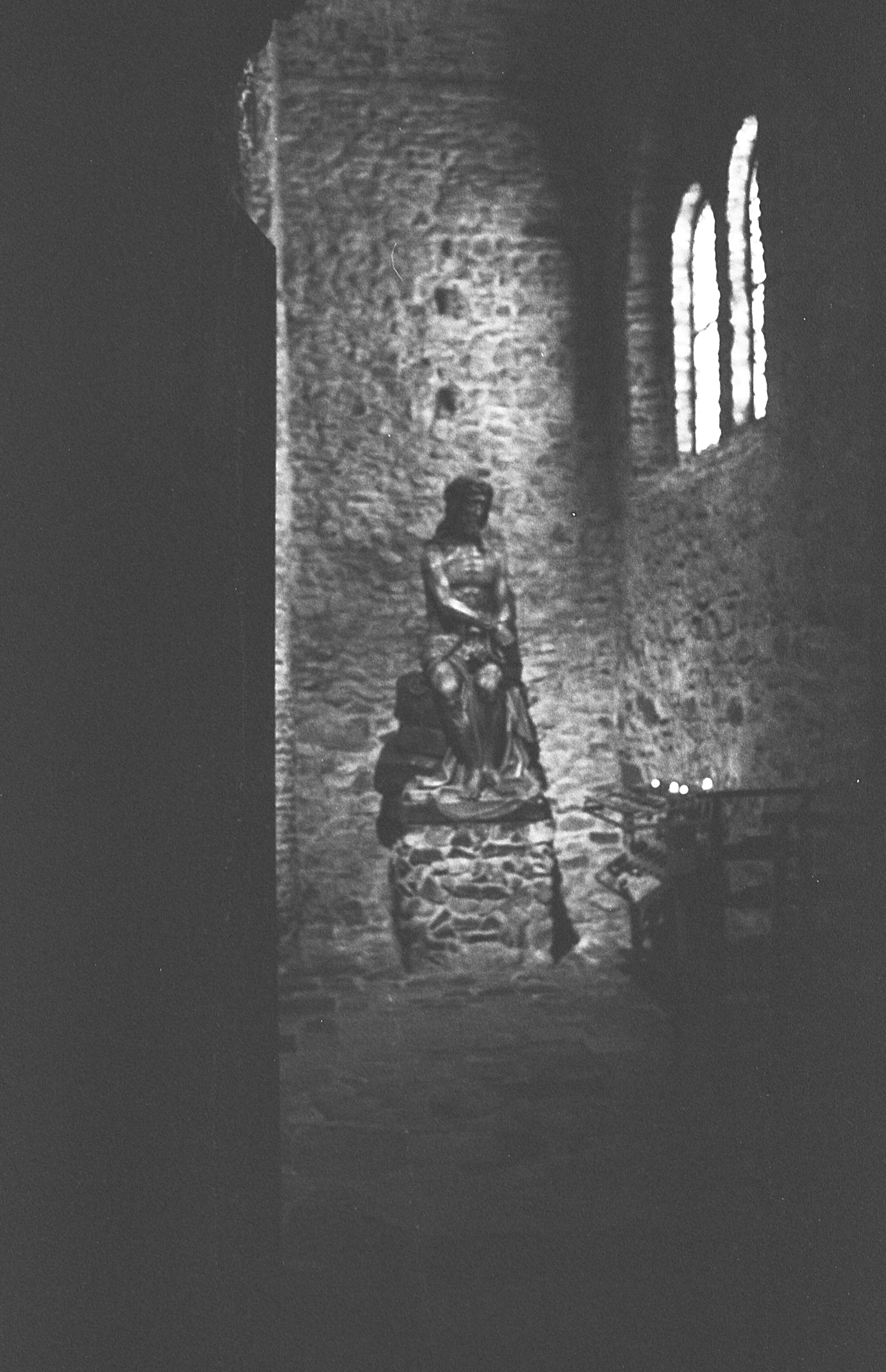 Stone statue in a dimly lit ancient stone building.