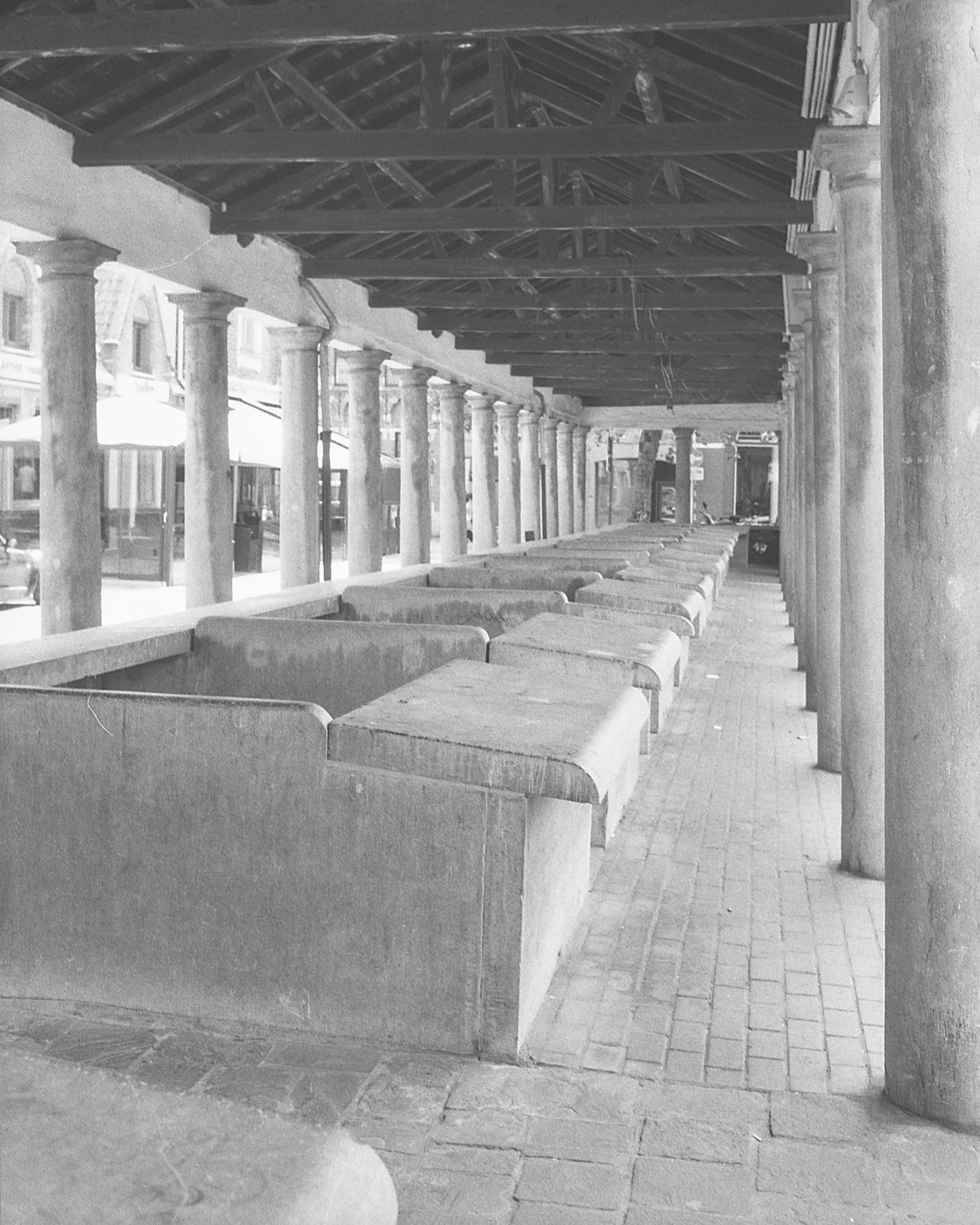 Covered market stalls with stone columns and brick floor