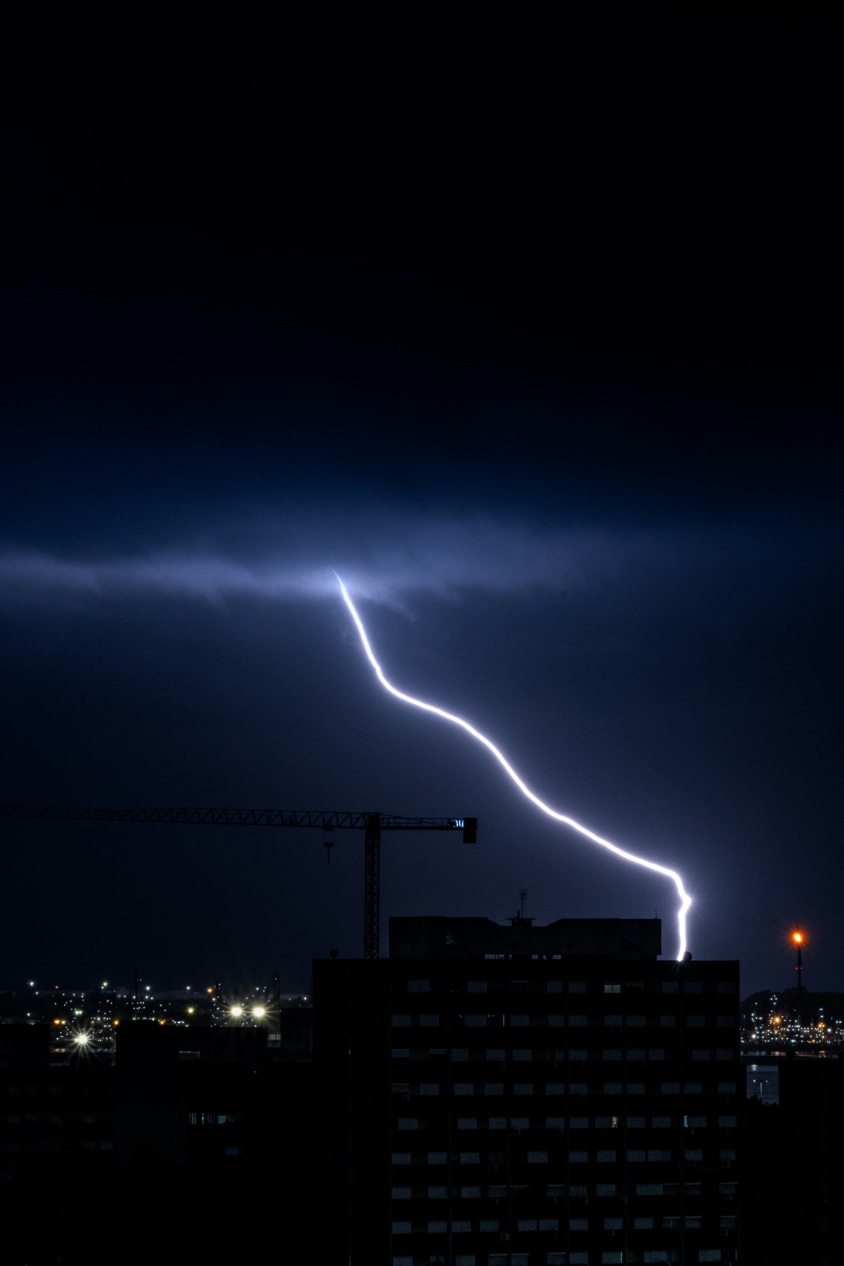 Lightning Arc Over a Distant City Silhouette