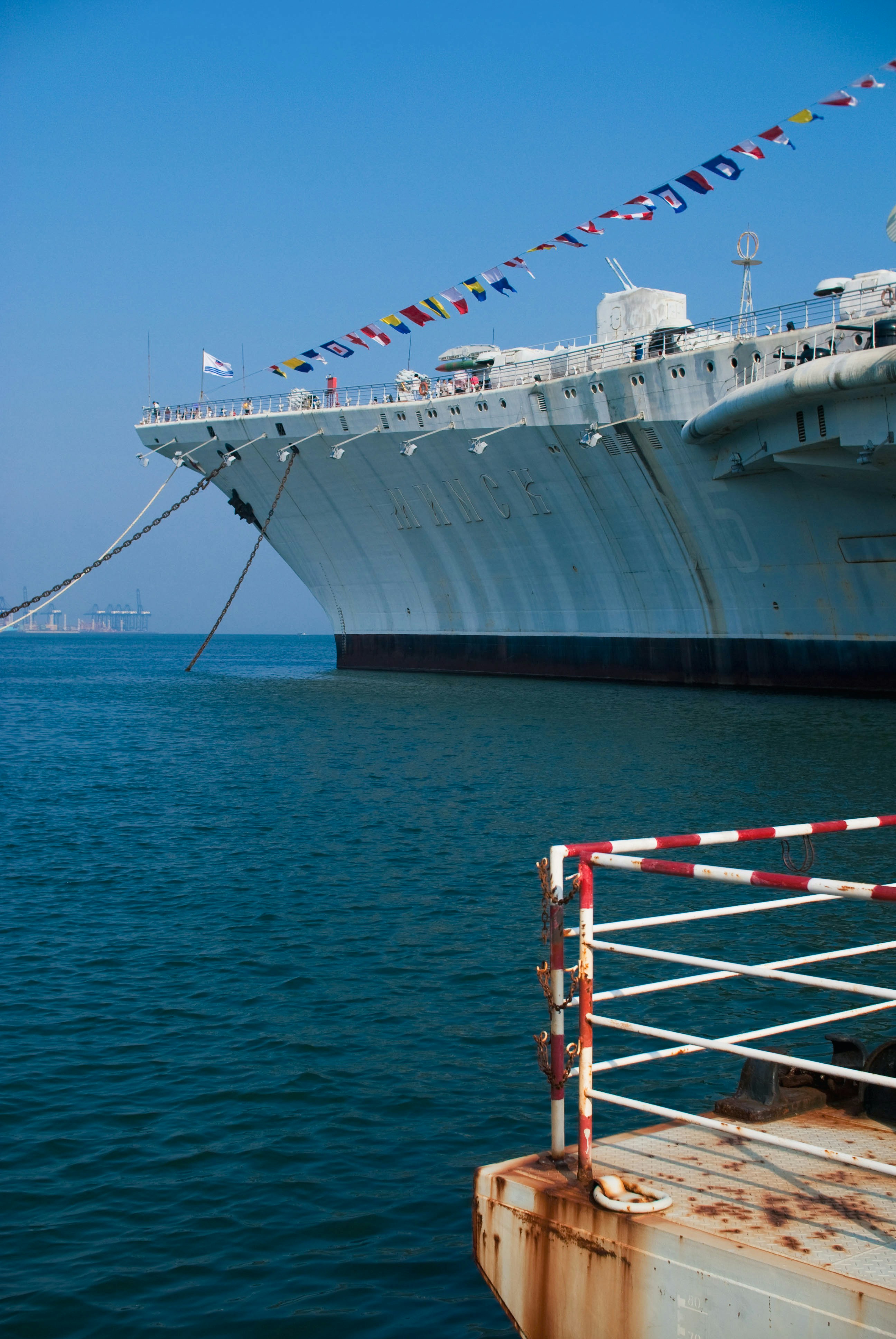 Docked giant: the forward hull of a warship anchored in calm blue waters