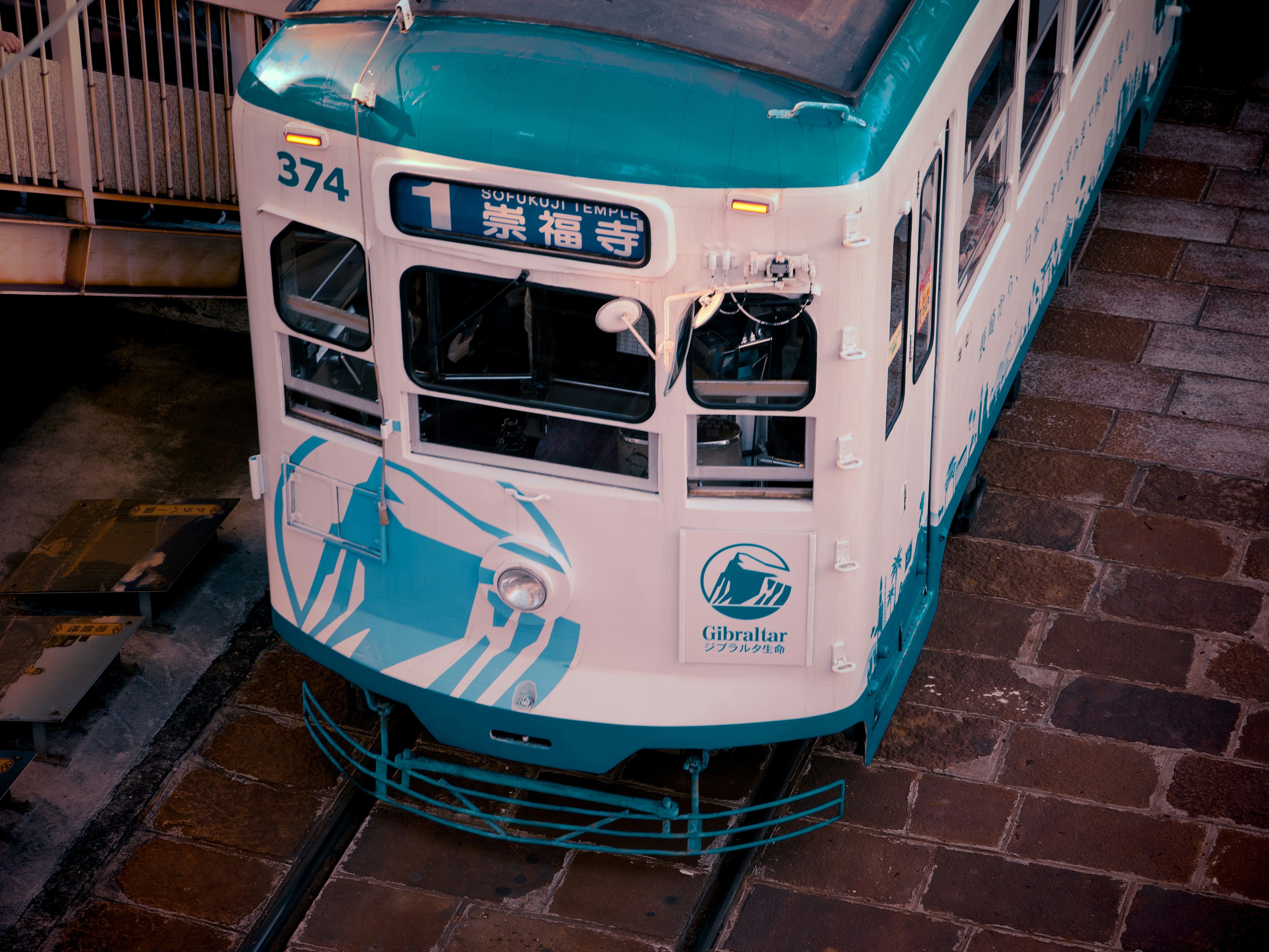 Blue and White Streetcar Streaking Over Cobbled Tracks