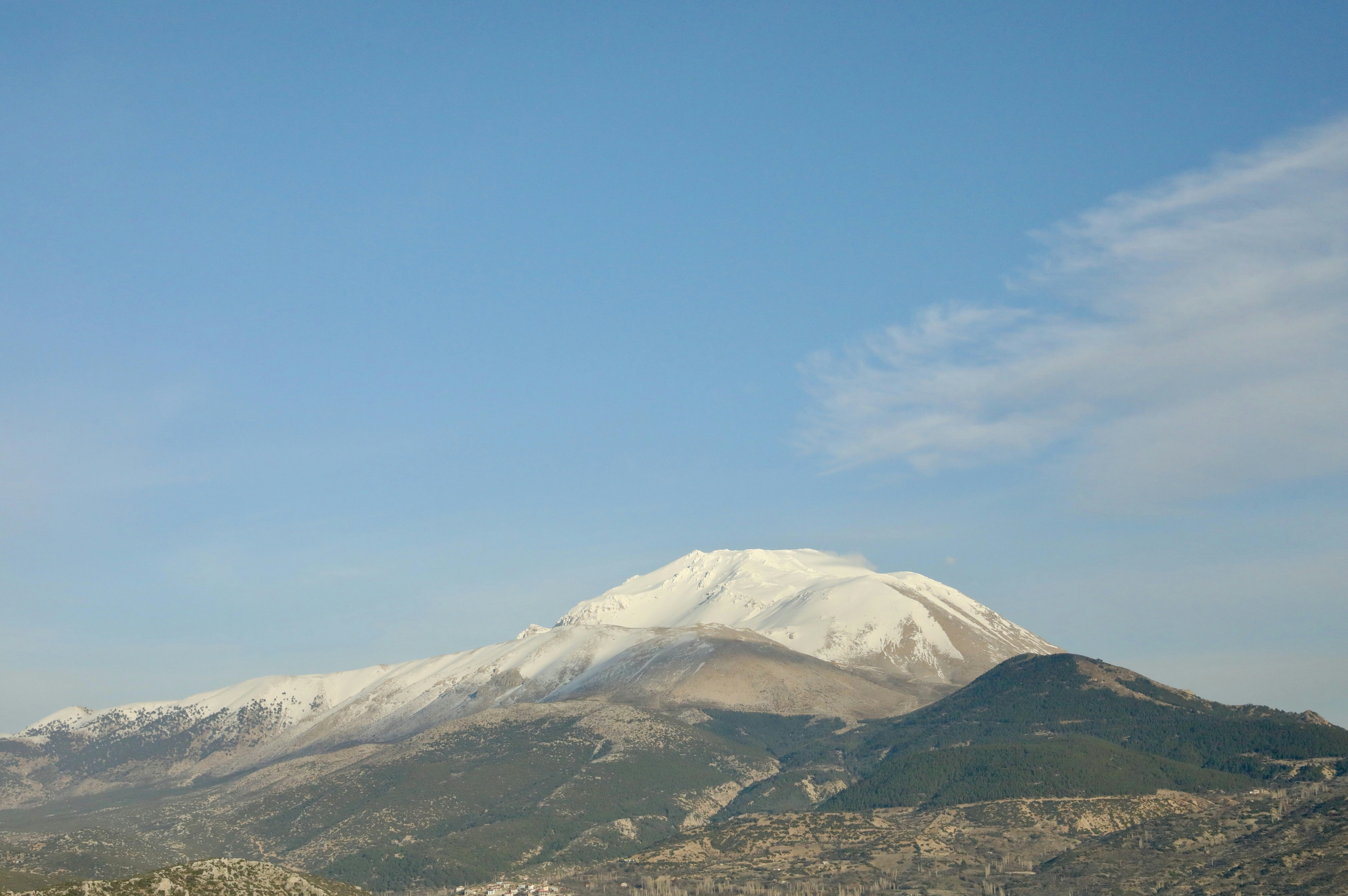 Snow-capped Peak Rises Above Rolling Foothills at Dusk