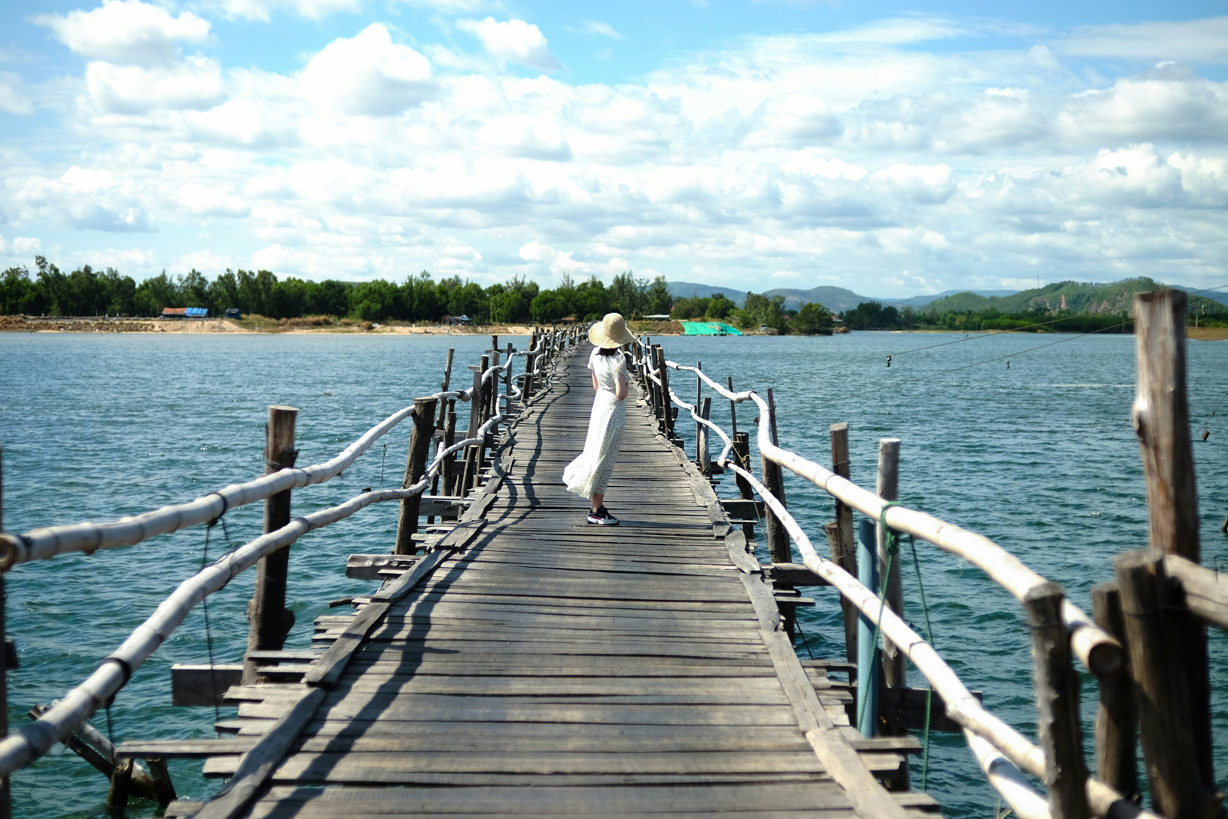 Lonely Walker on a Wooden Causeway Over a Calm Lake