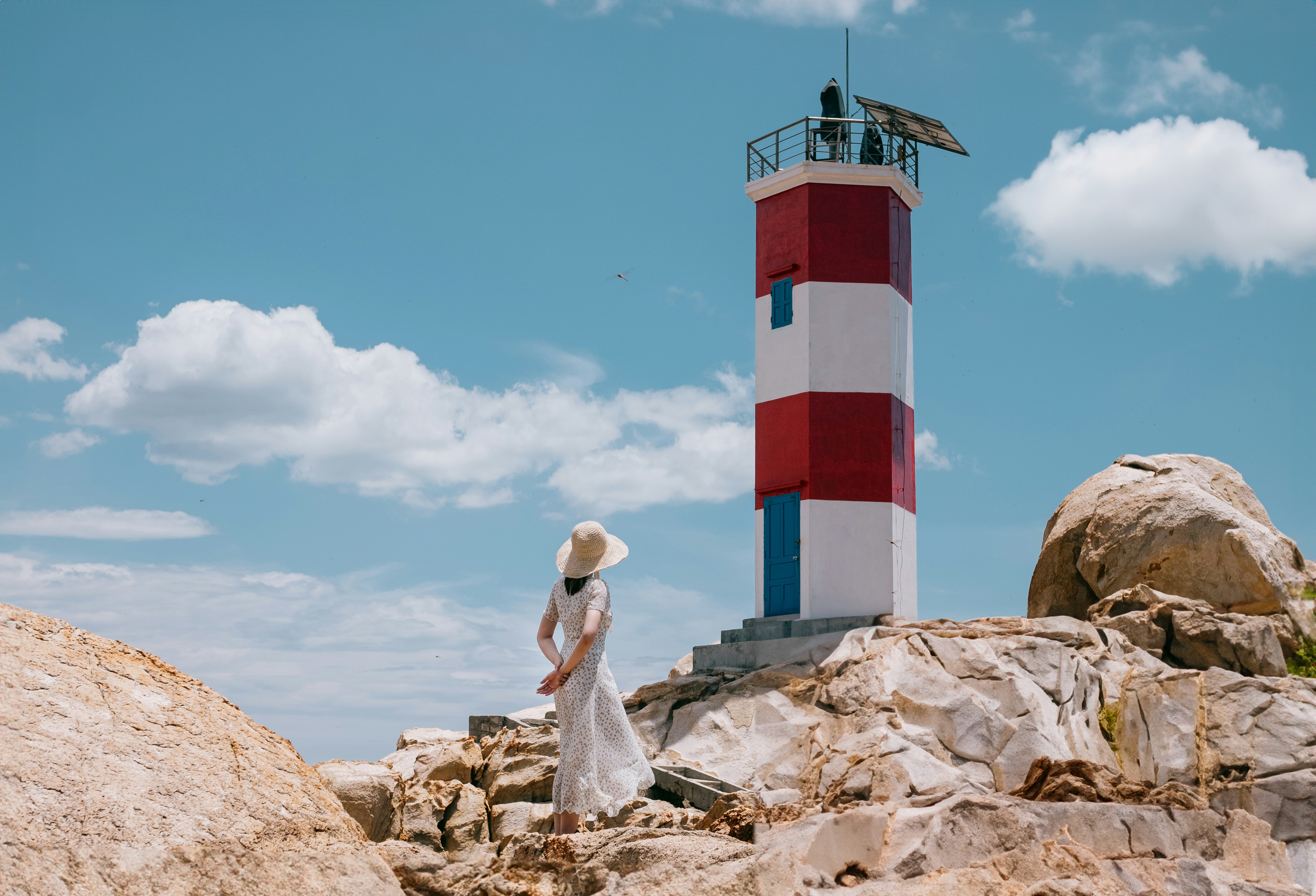 Lighthouse and Lithe Figure: A Seaside Portrait by the Rocking Shore