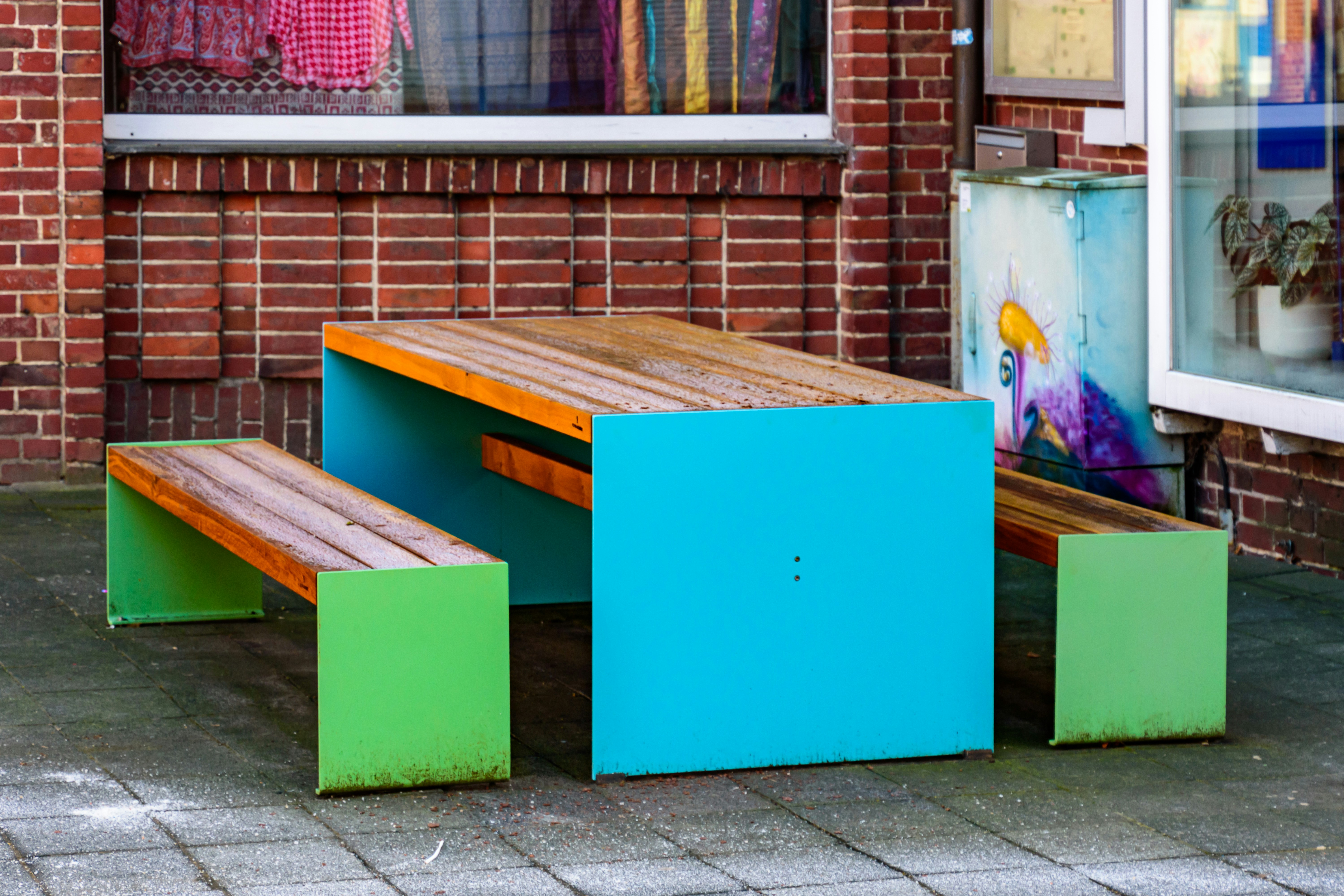 Playful Picnic Tables, Neon Green and Sky Blue, Outside a Brick-Wurld Corner