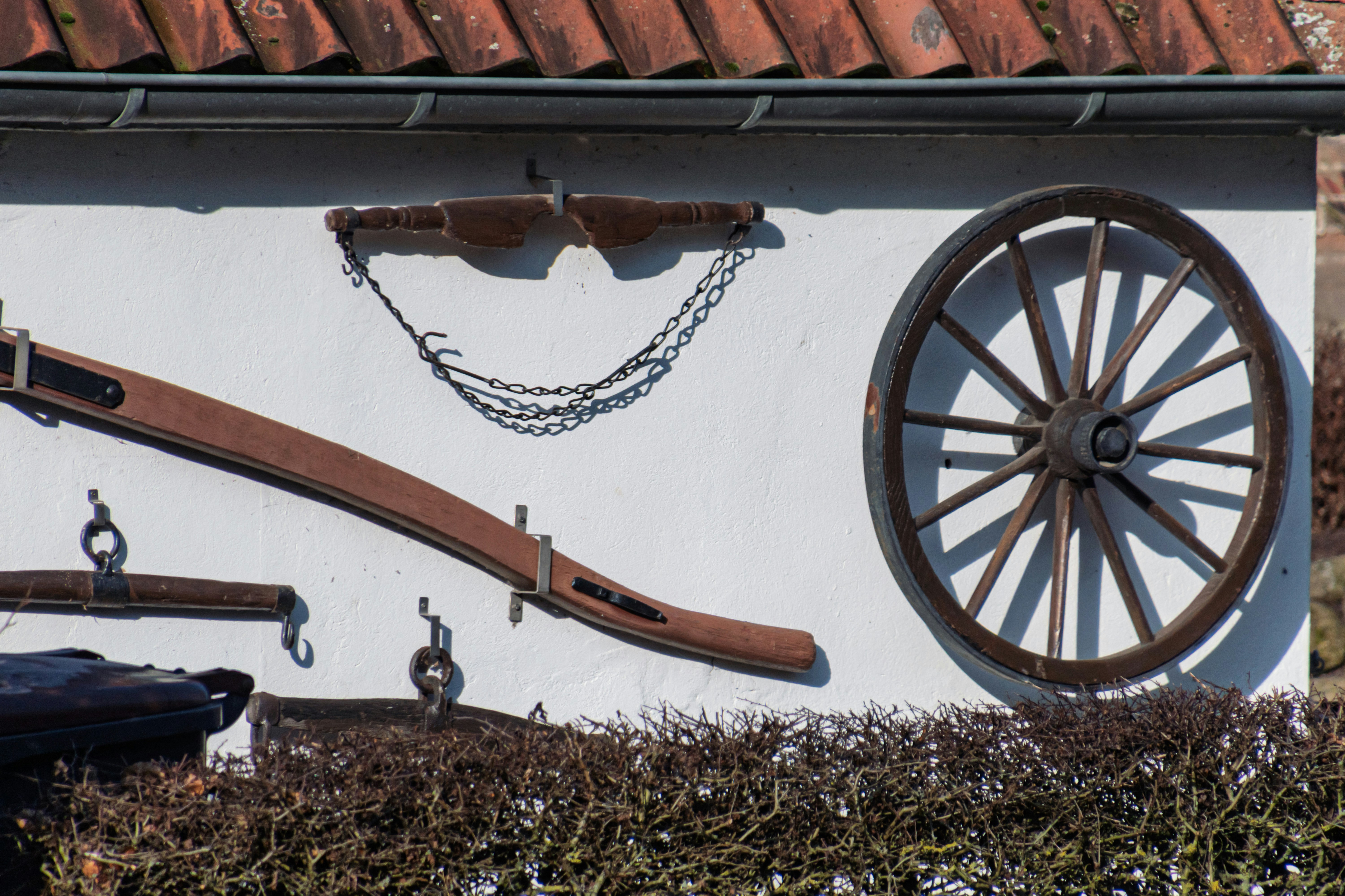 Old Wheel and Curved Wooden Tooling Adorn a White Wall