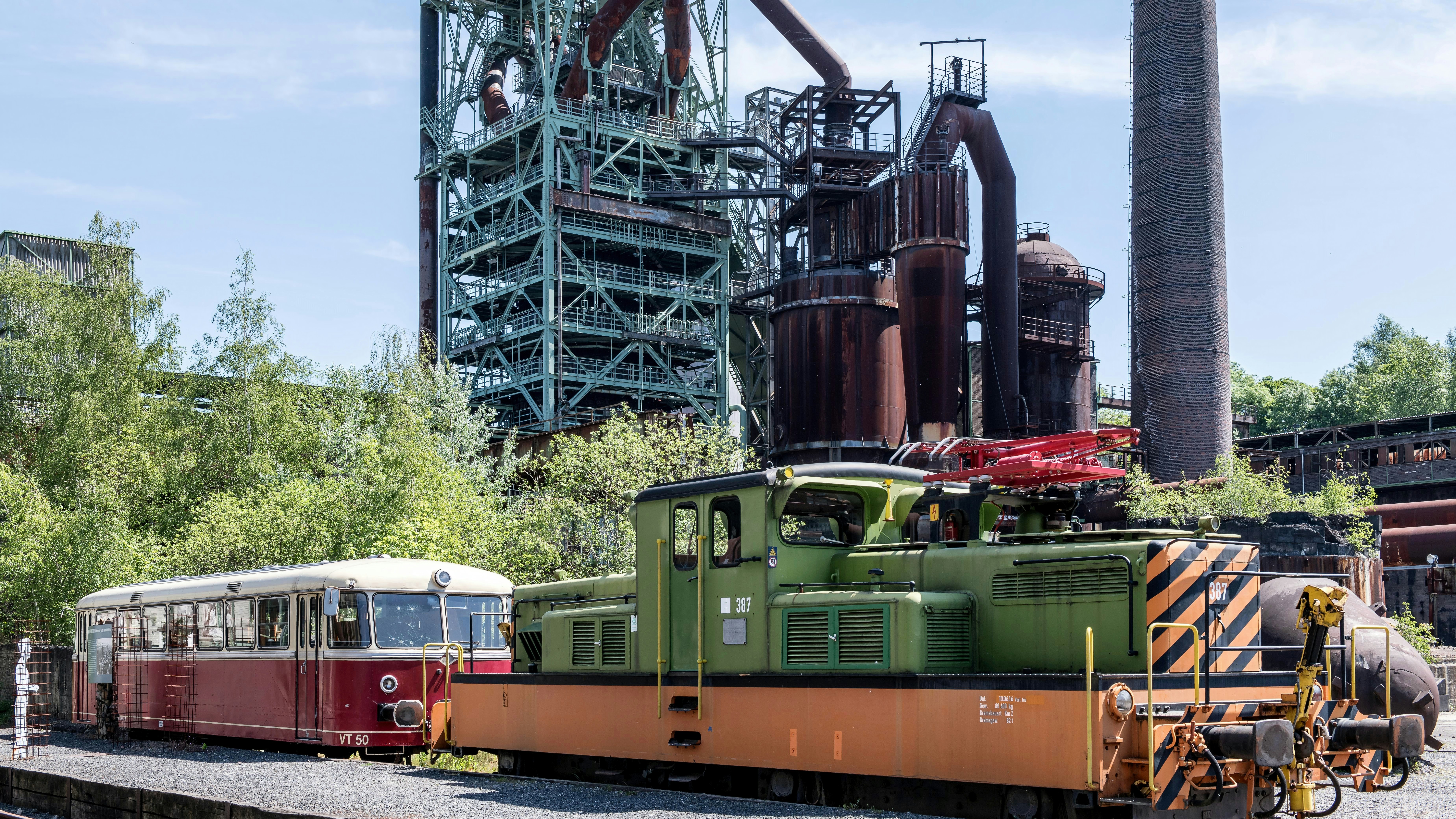 Restored railcar meets towering industrial silhouettes amid a factory yard